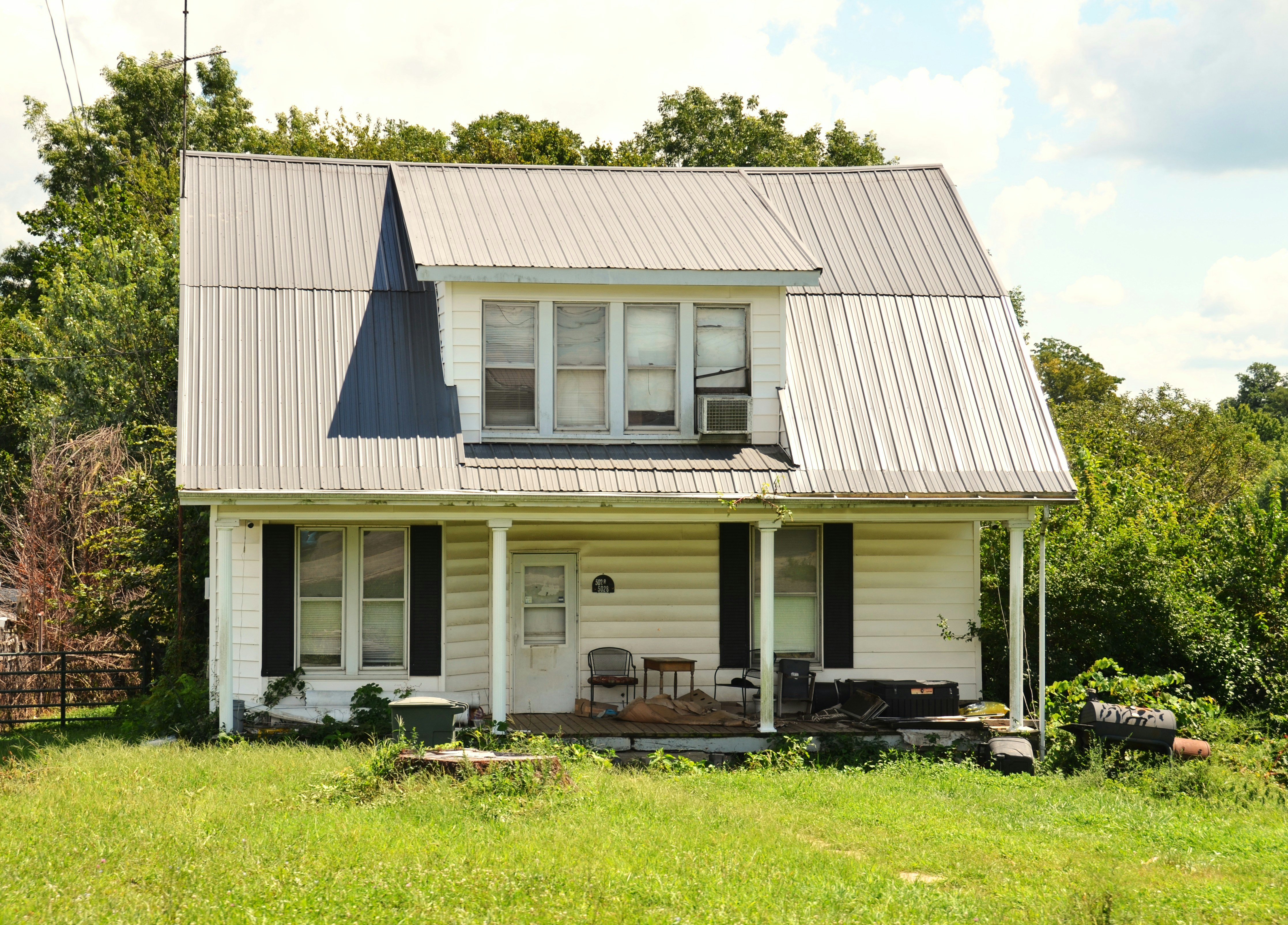 Abandoned Cottage with Weathered Metal Roof and Overgrown Lawn