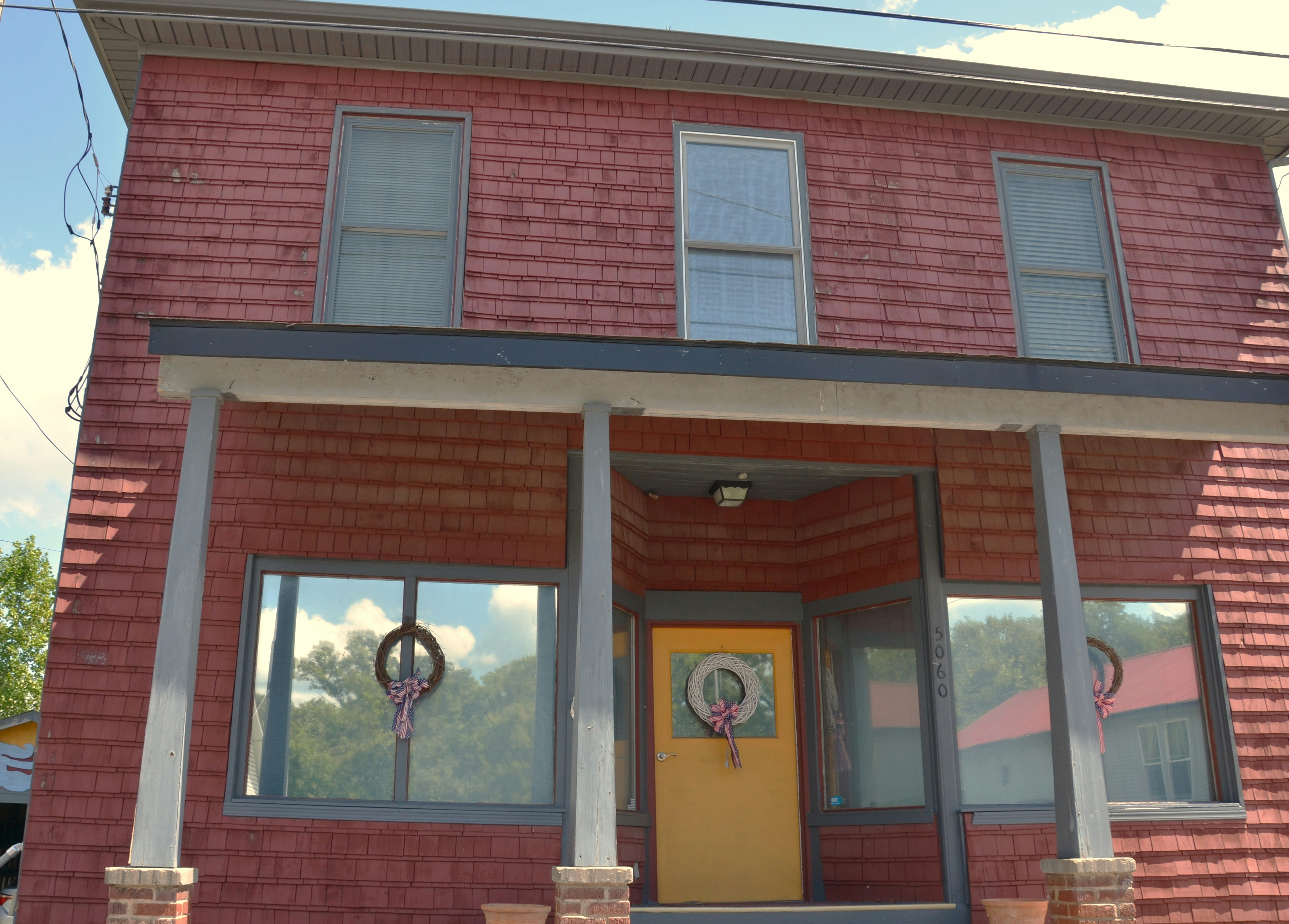 Small-town Red Brick House with Bright Yellow Door Framed by Wreaths