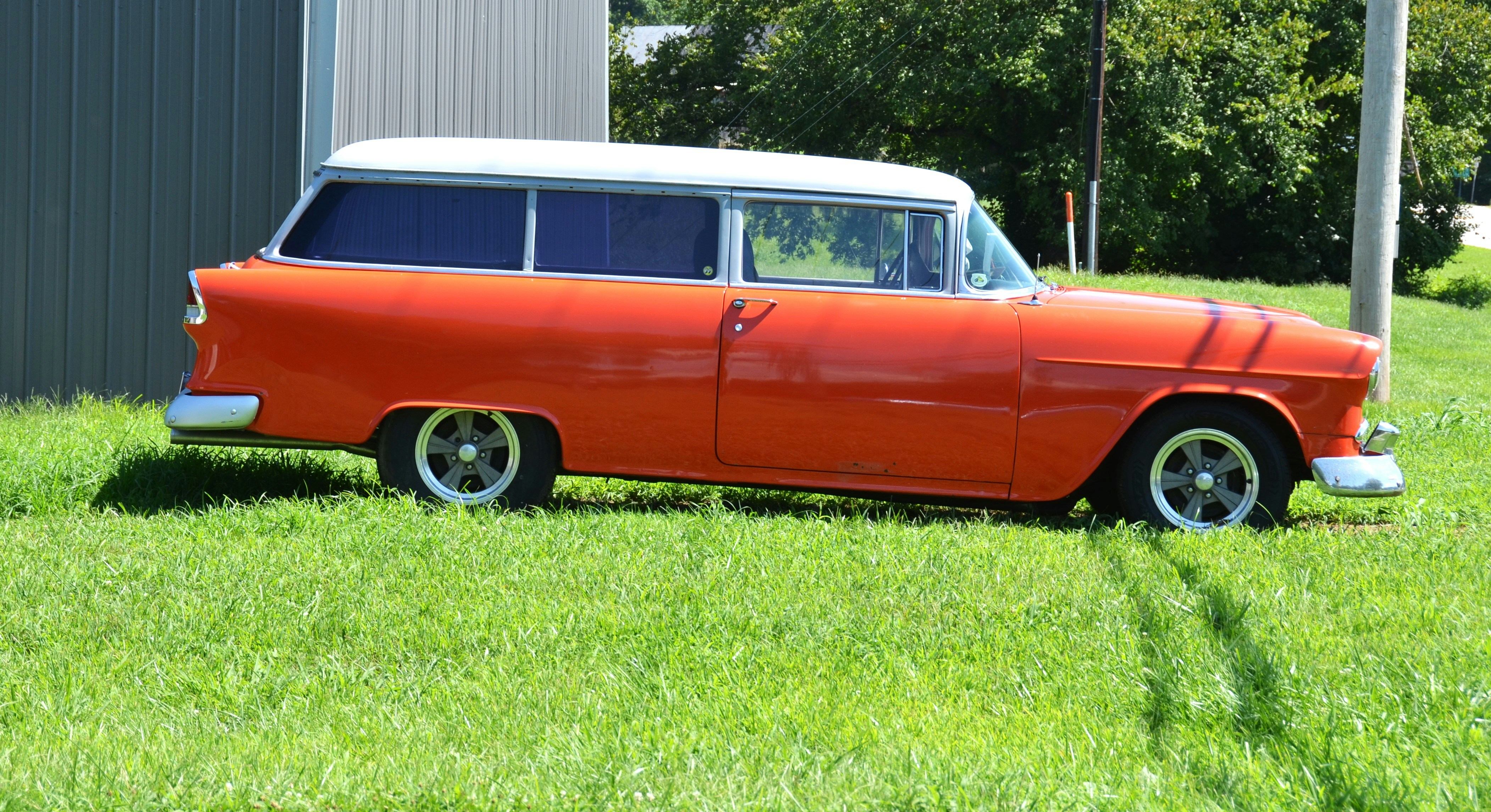 Orange Classic on Green: A Mid-Century Sedan Resting in Sunlit Grass