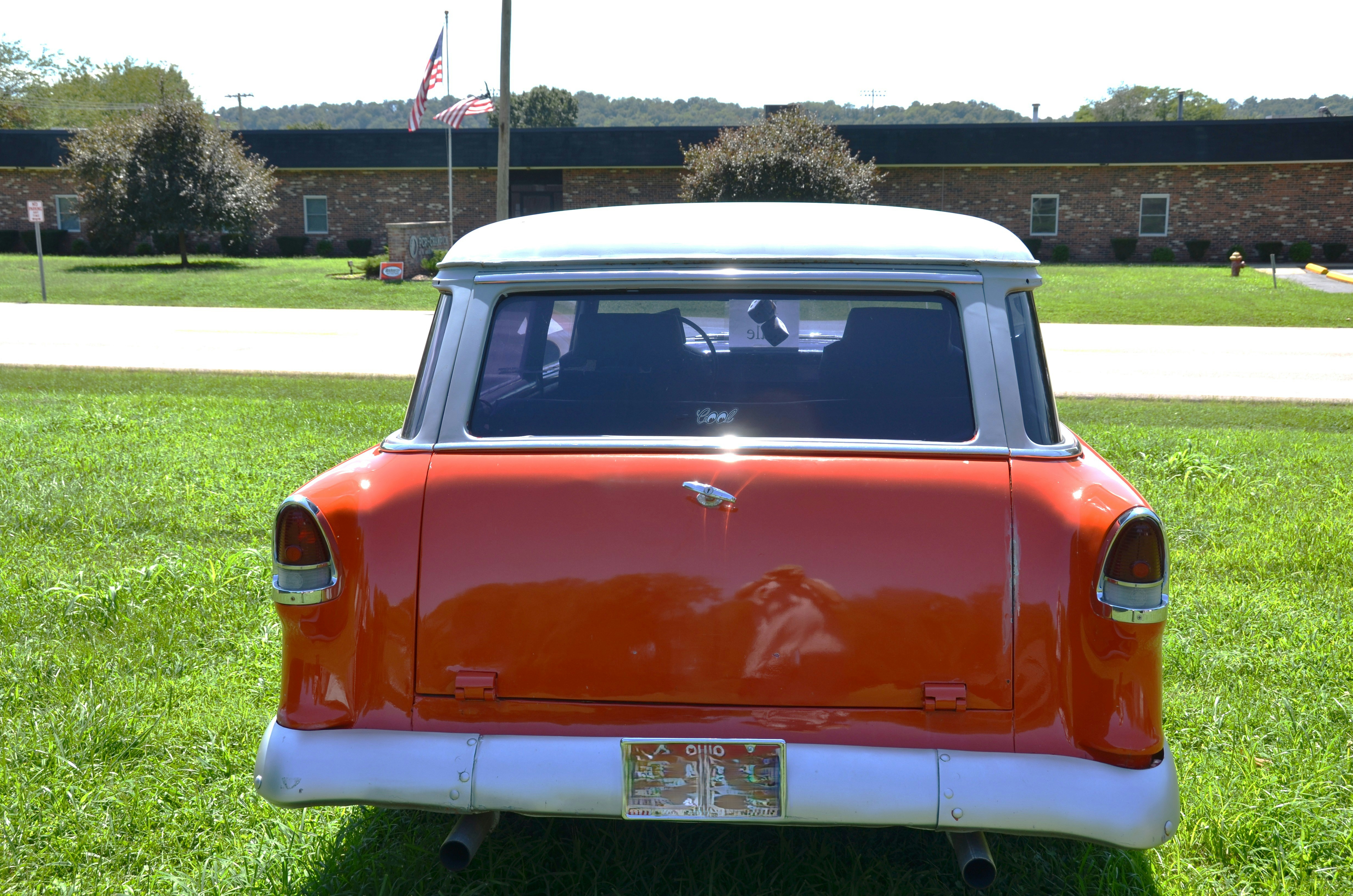 Backyard Classic: Orange Sedan Resting Under Midday Sun
