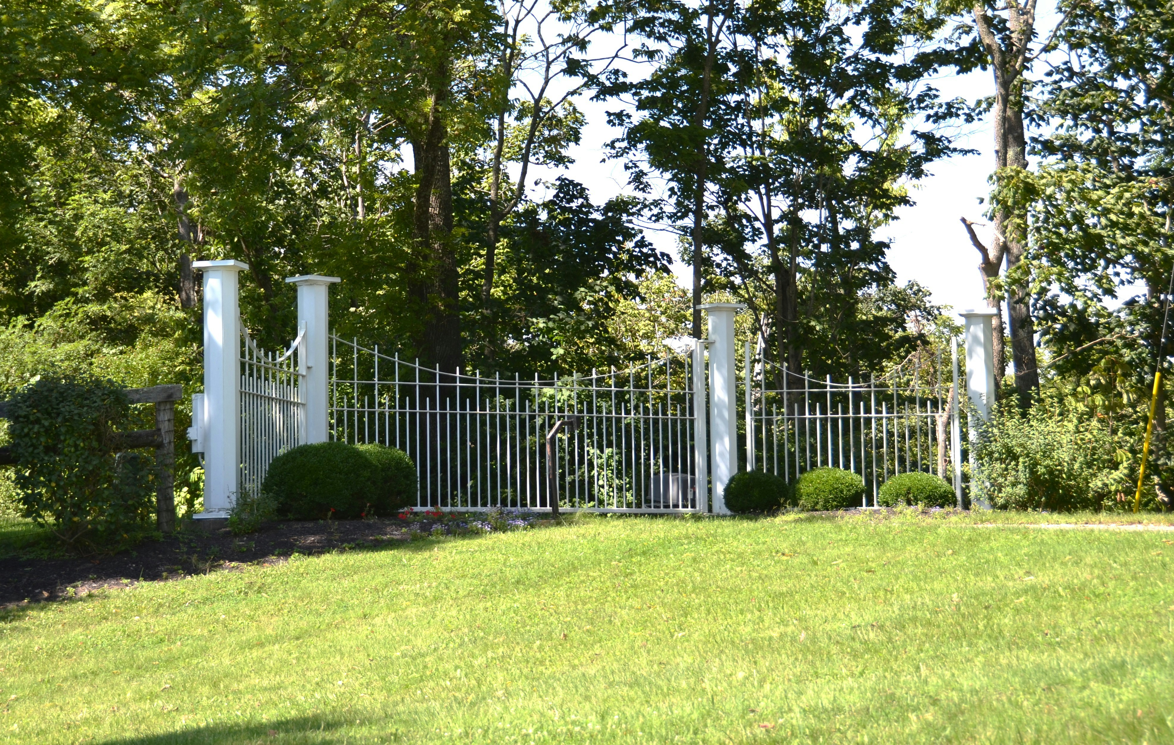  gated garden gateway with manicured hedges and white iron fence
