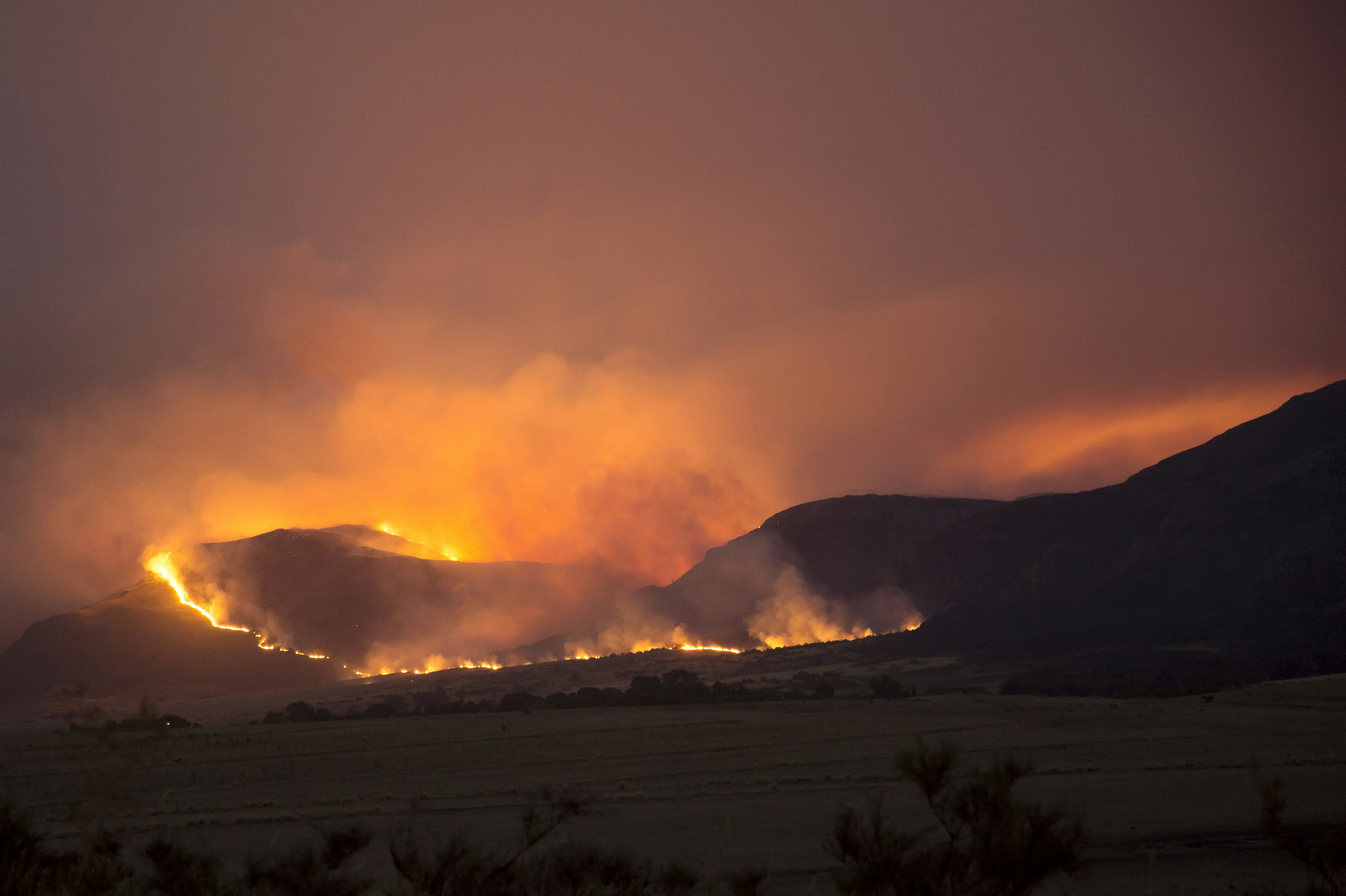 Lava glow over foothills: a distant wildfire silhouette