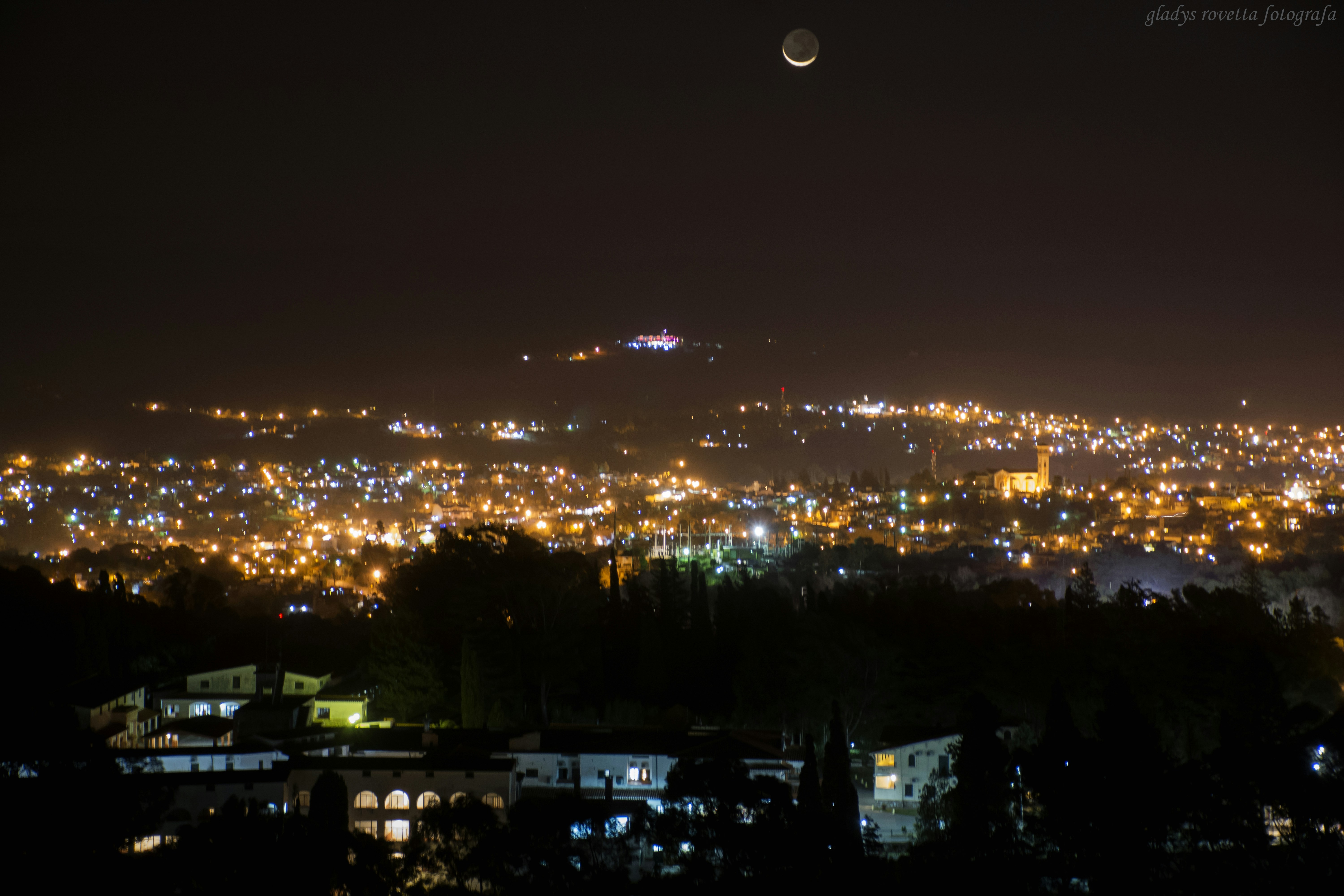 Moonlit Cityscape: A Crescent Above the Glow