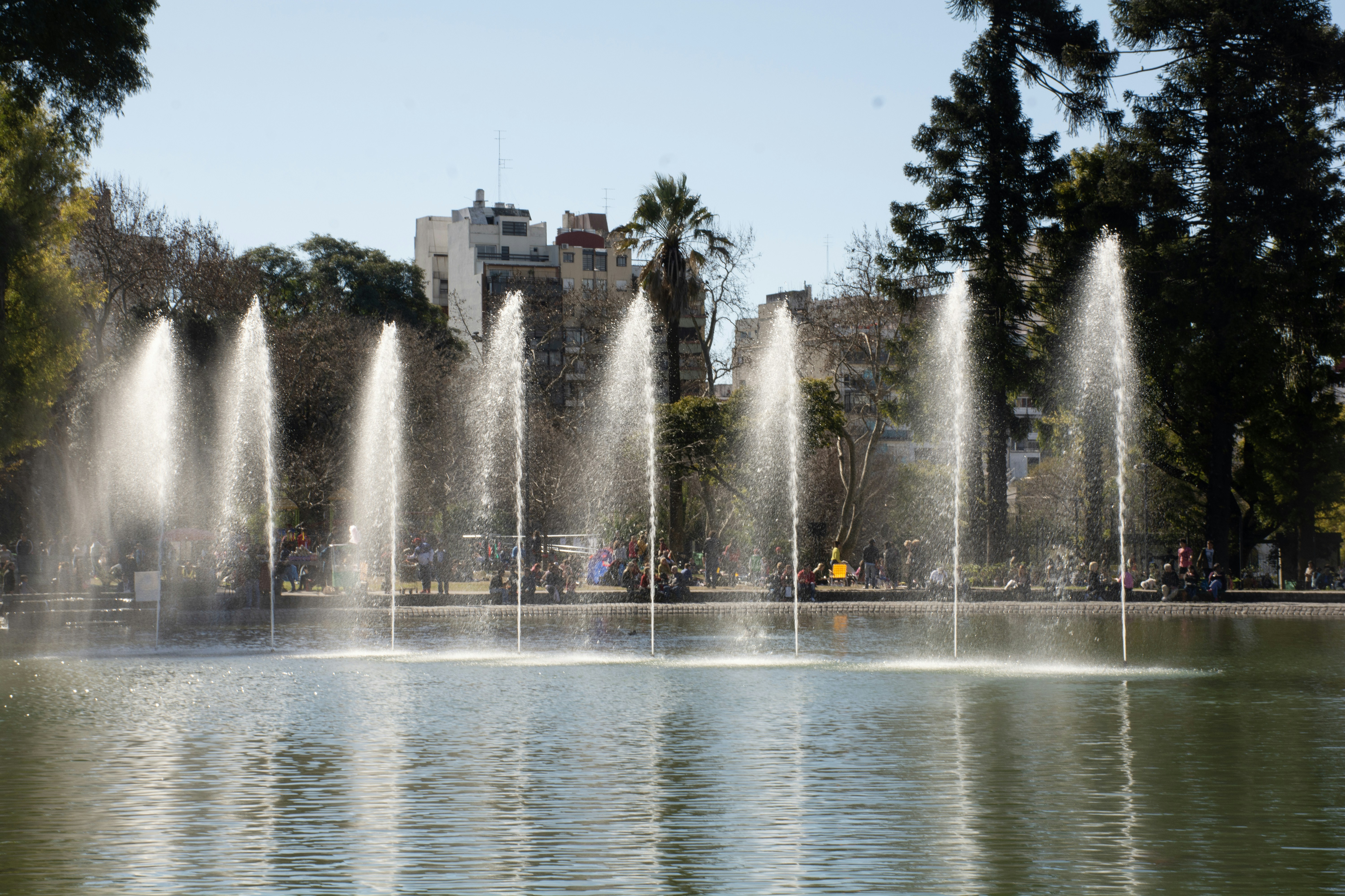 Symmetrical Spray: A Row of Fountain Arches Over a Quiet Lake