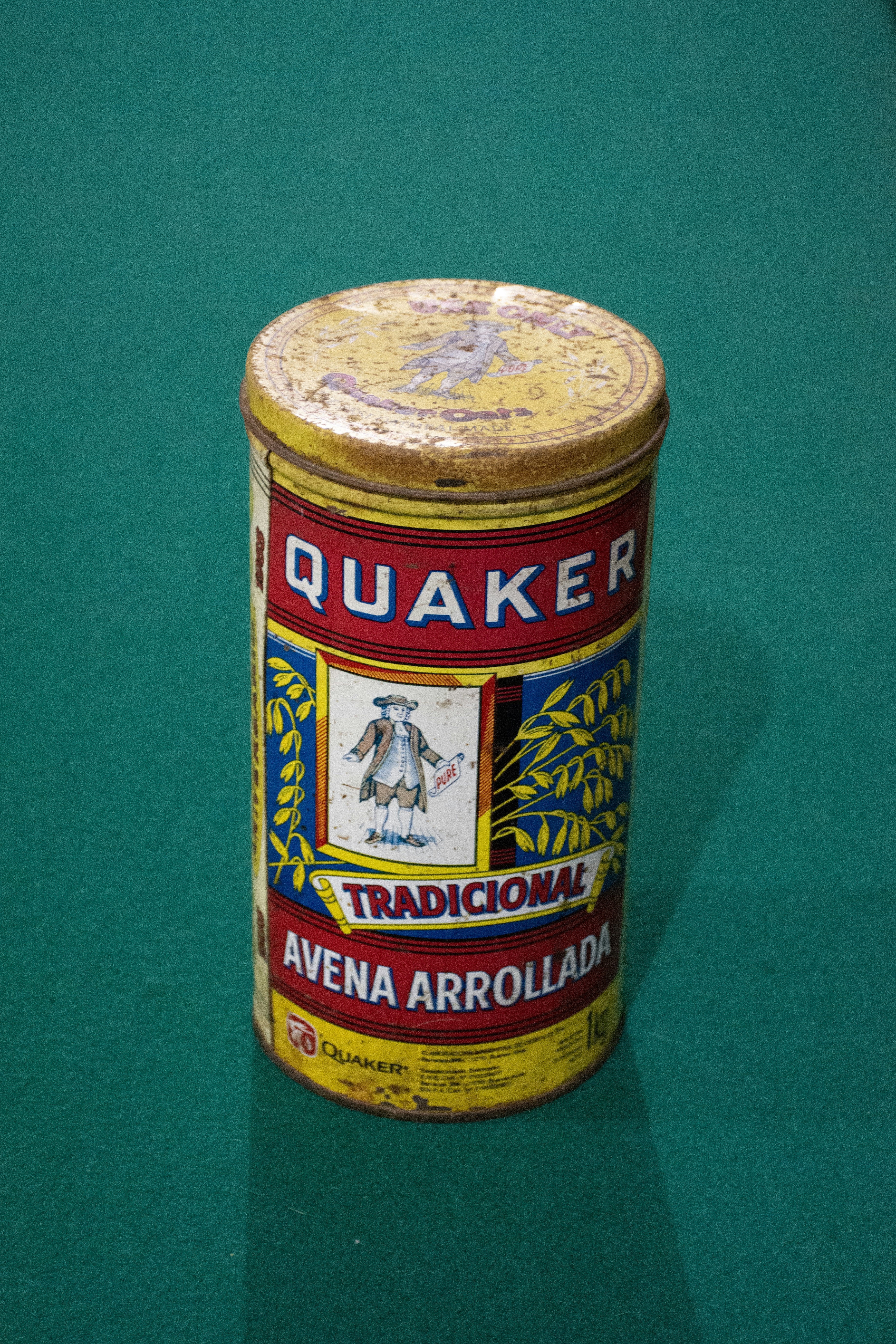 Aged Quaker Tin: Vintage Avena Arrollada Can Standing on Green Felt