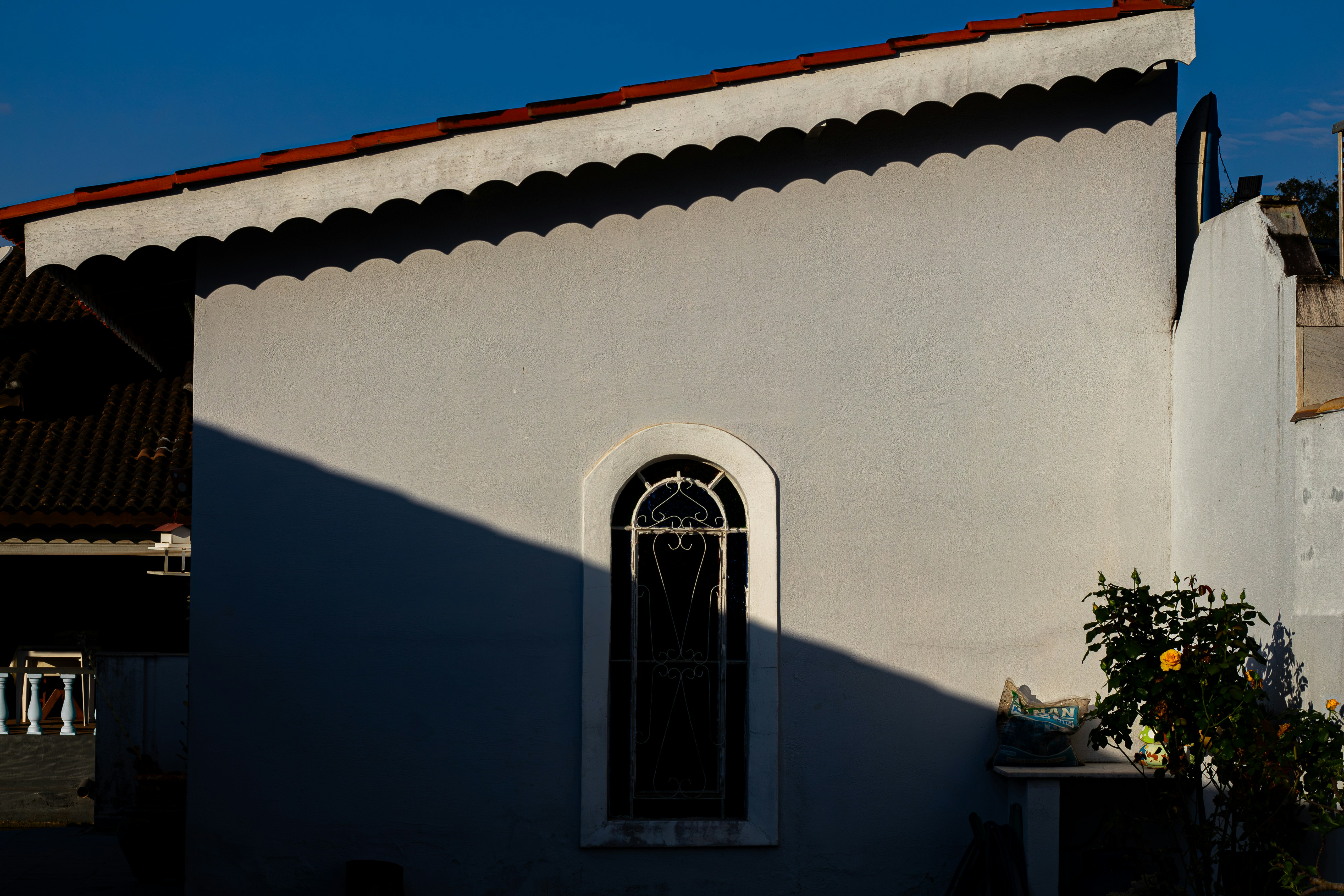 Shade and Silhouette: The Arched Window in a Sunlit Facade