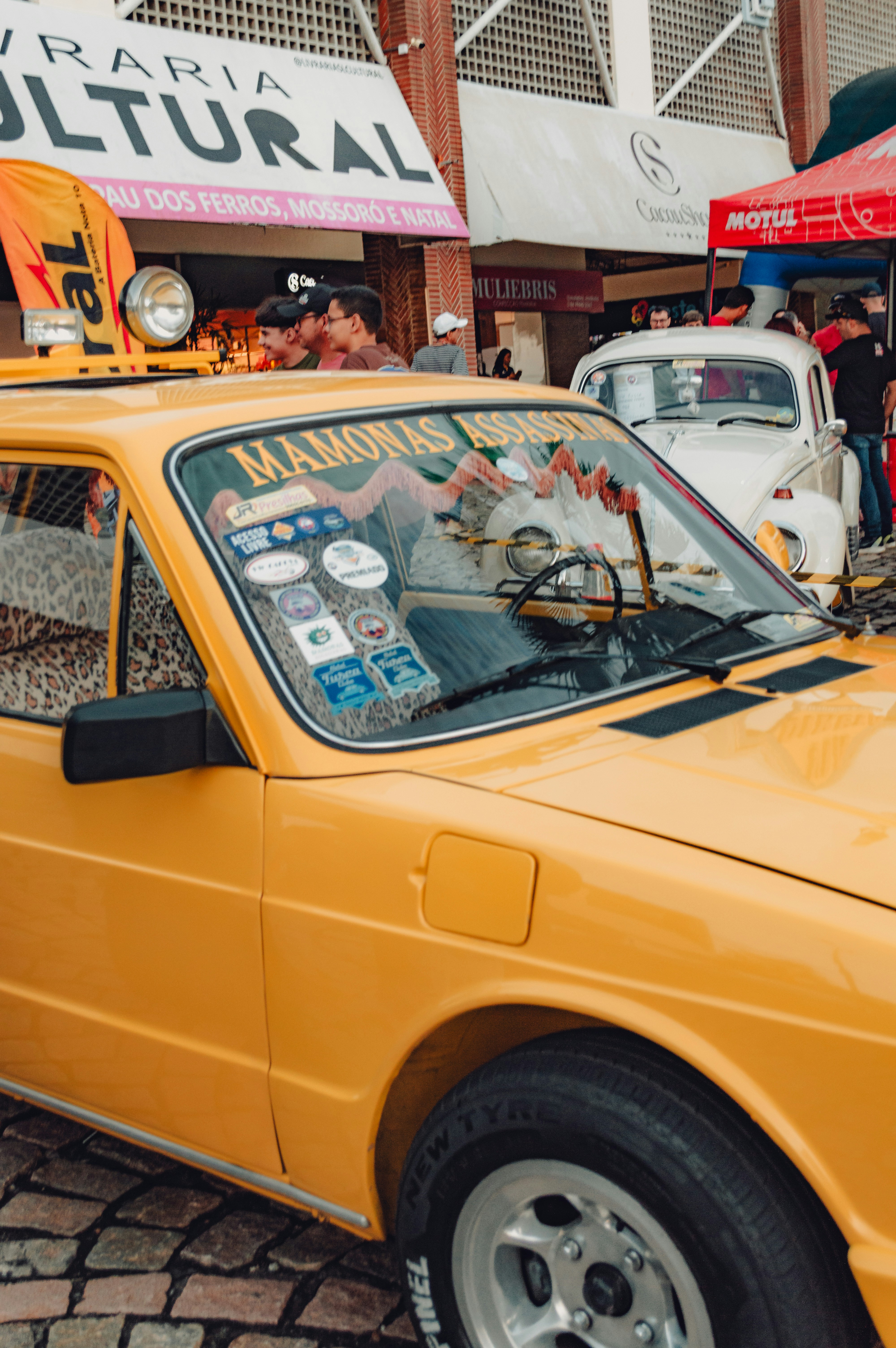 Yellow taxi cockpit: stickers, windshield reflections and crowd at a street fair