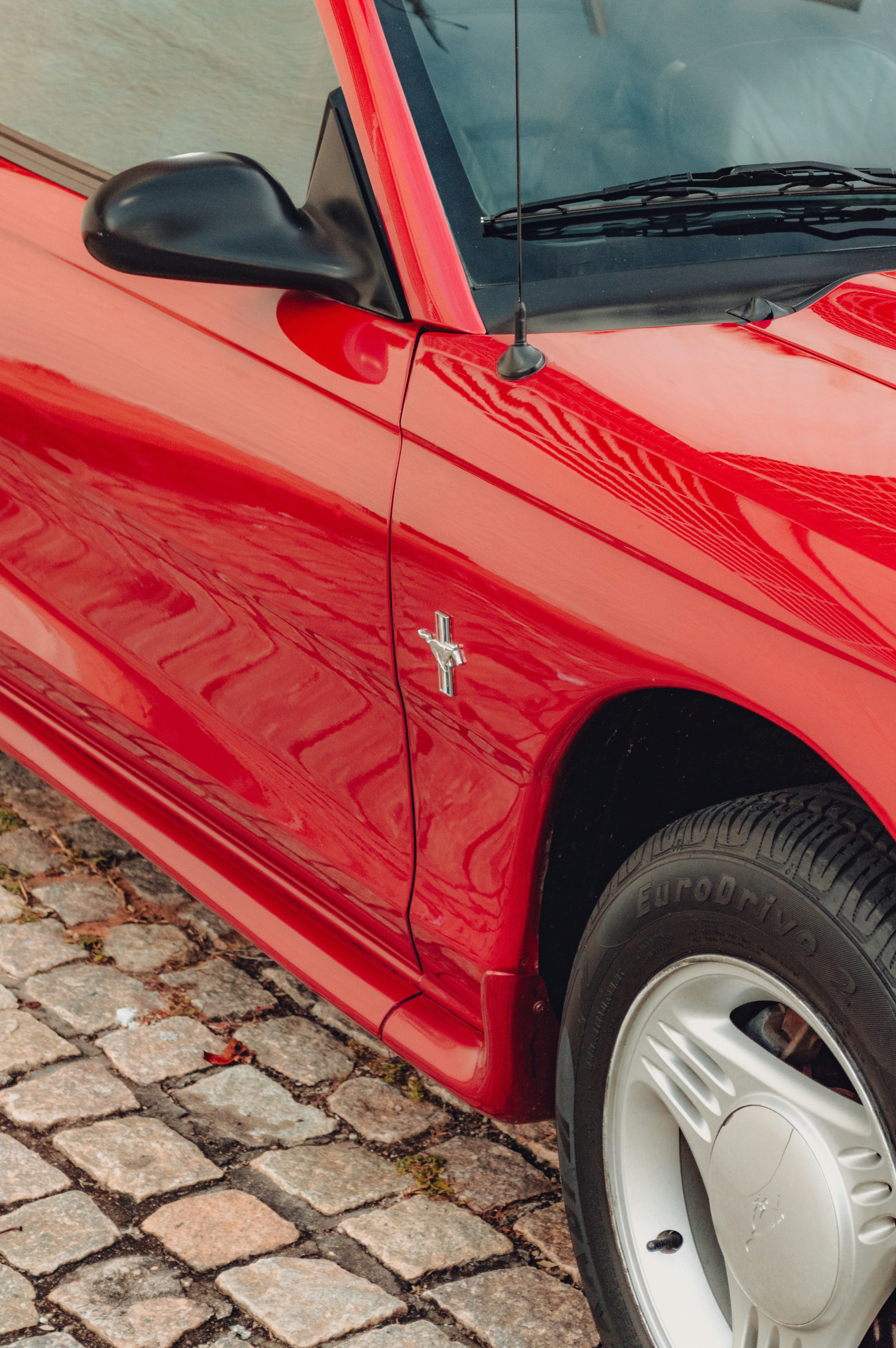 Scarlet Mustang Reflections: A Close-Up of Curves, Chrome, and Chrome-Toned Body Lines