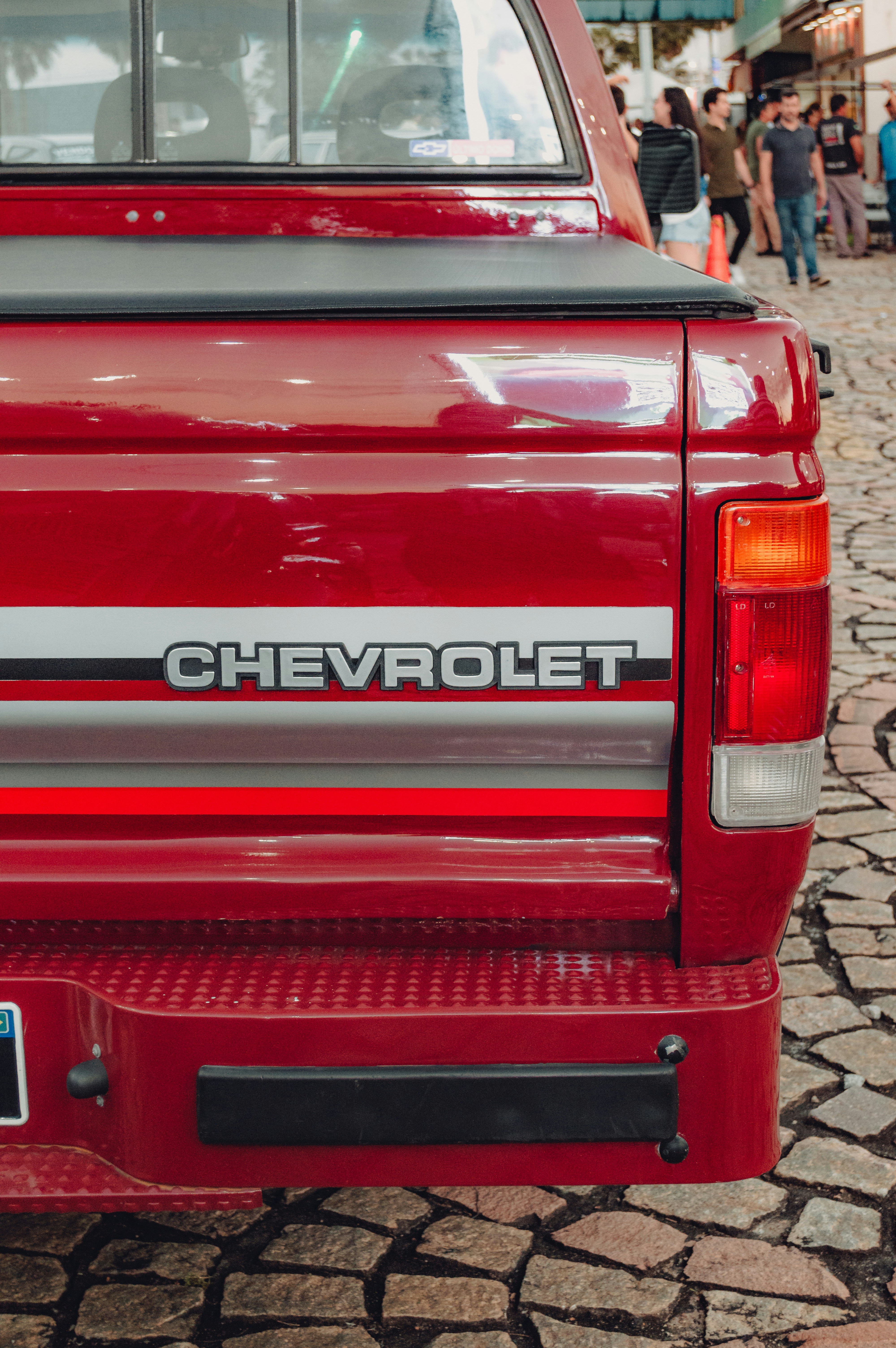 Red Chevrolet Tail, Concrete Courtyard, and Parked Crowd