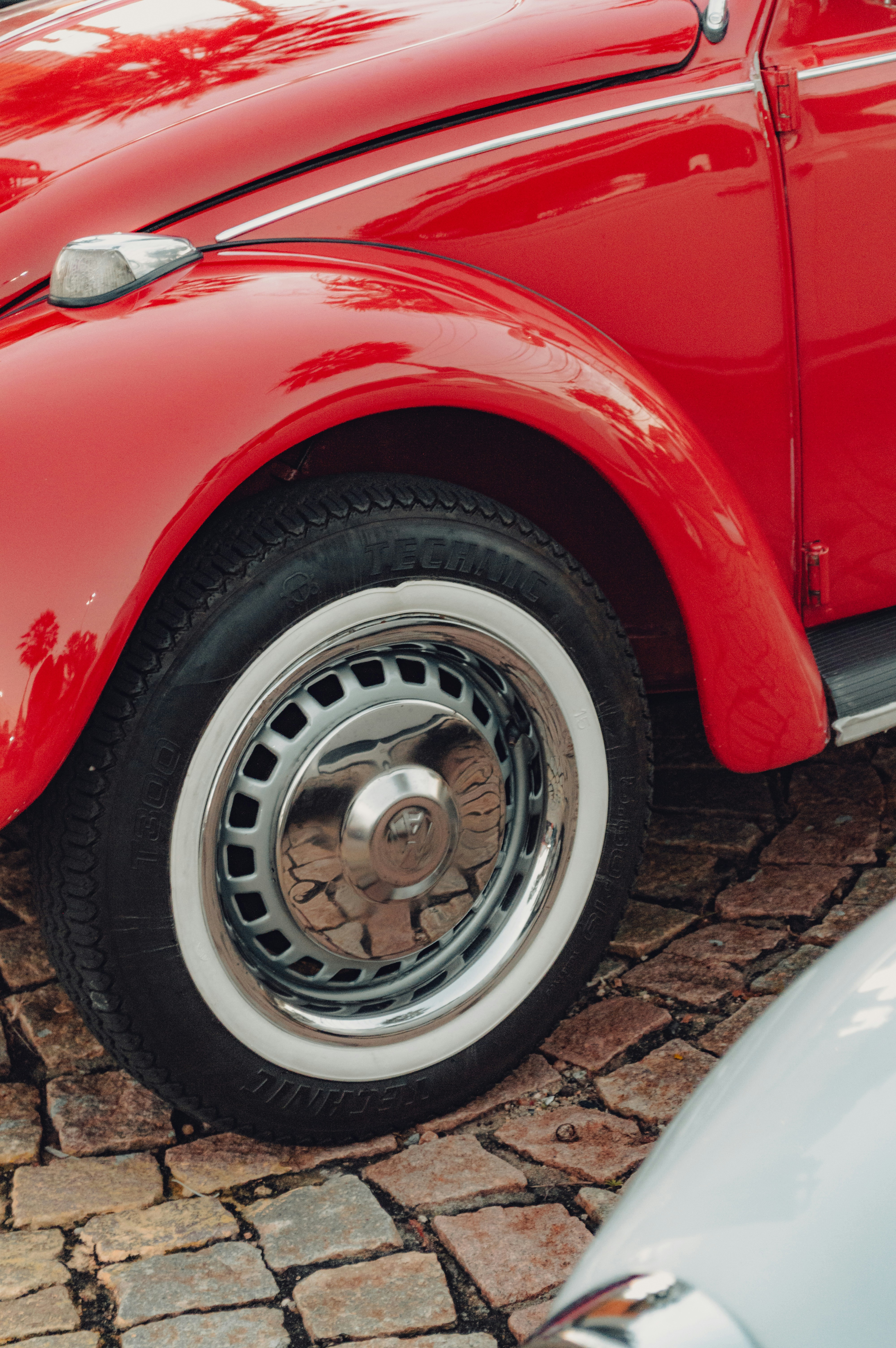 Rosy Curves and Chrome: The Front Wheel of a Classic Red Automobile