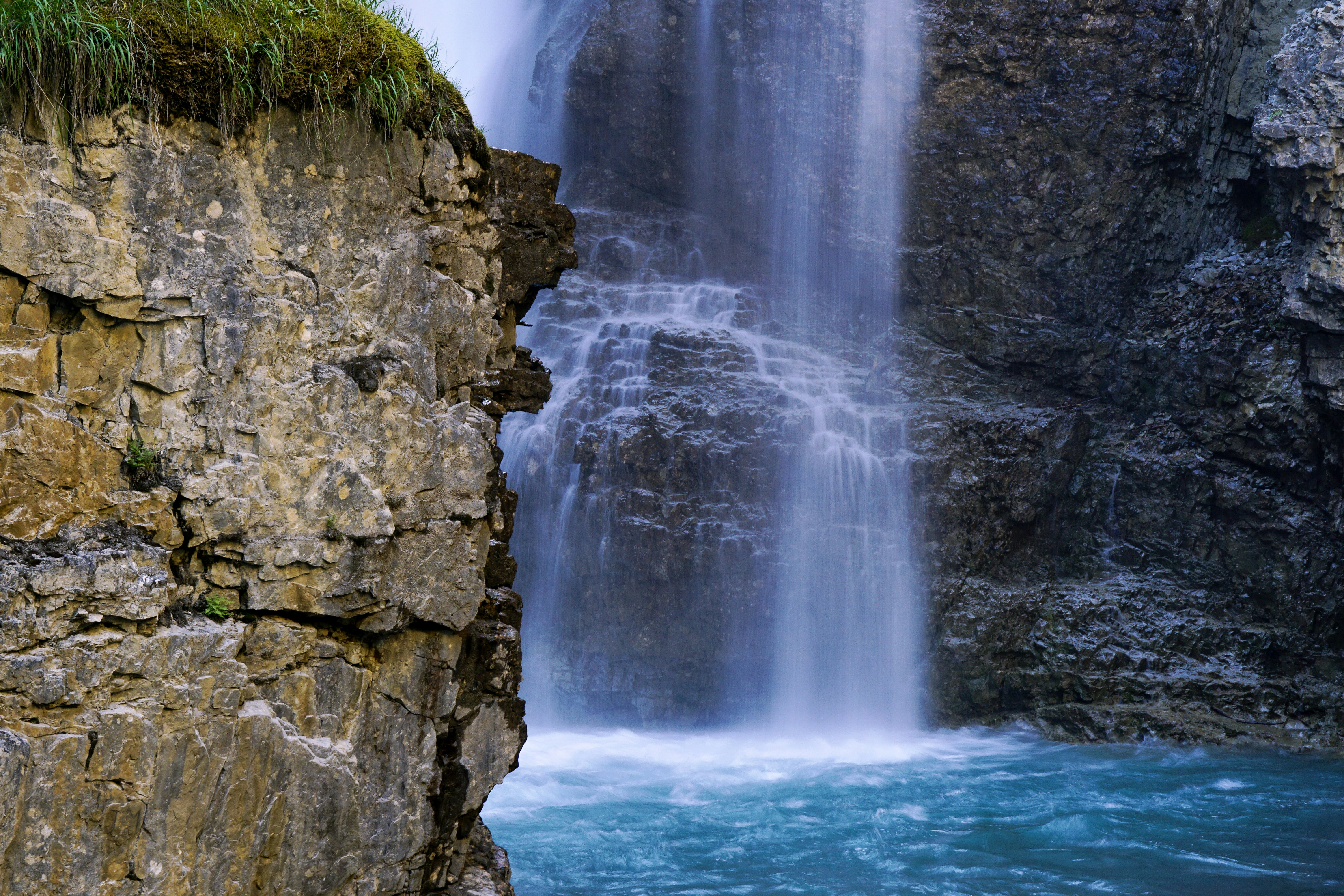 Cascade at the Edge: A Narrow Cliff Drops into Turquoise Veil