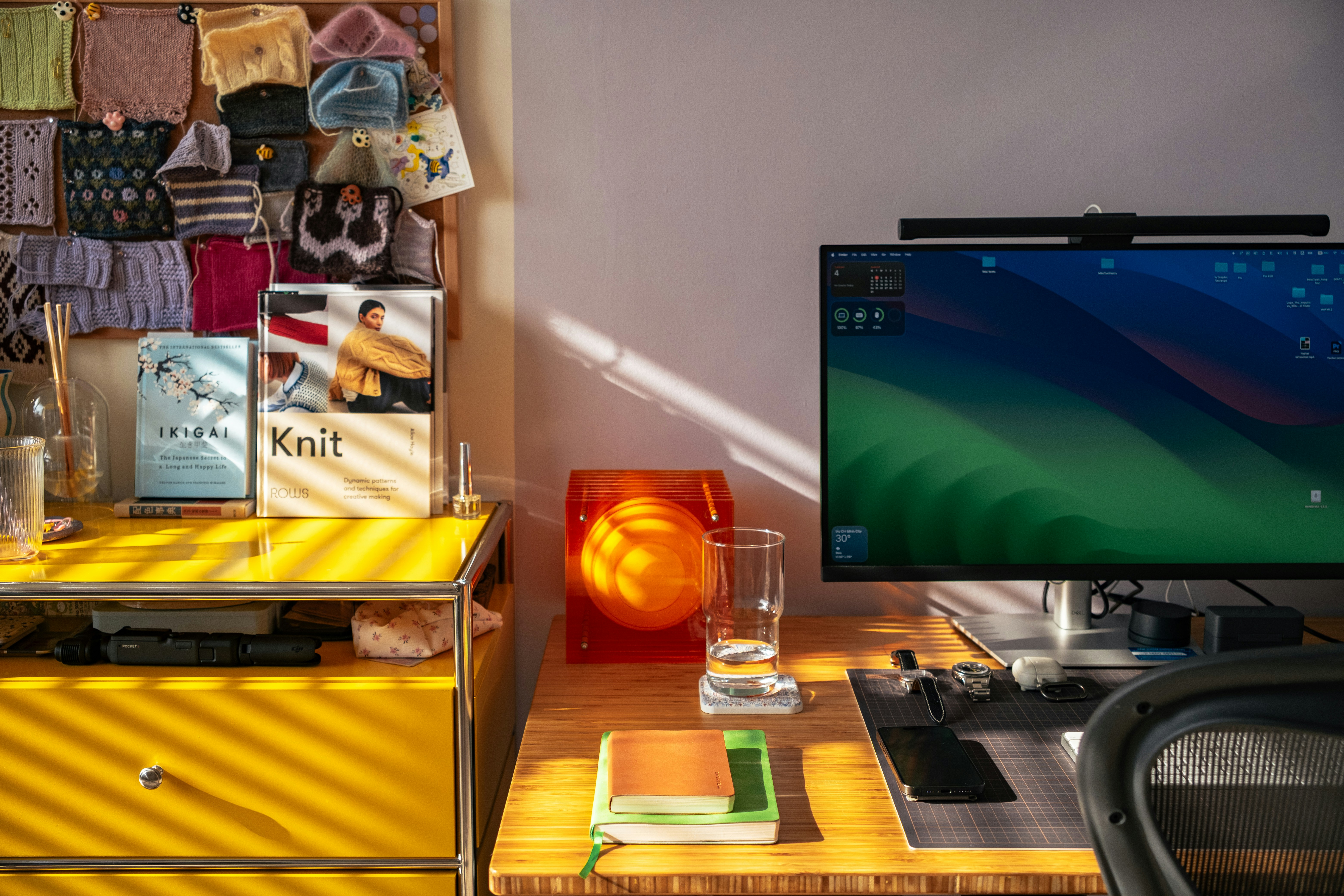 Sunlit workspace with knitted fabrics display and electronic desk setup