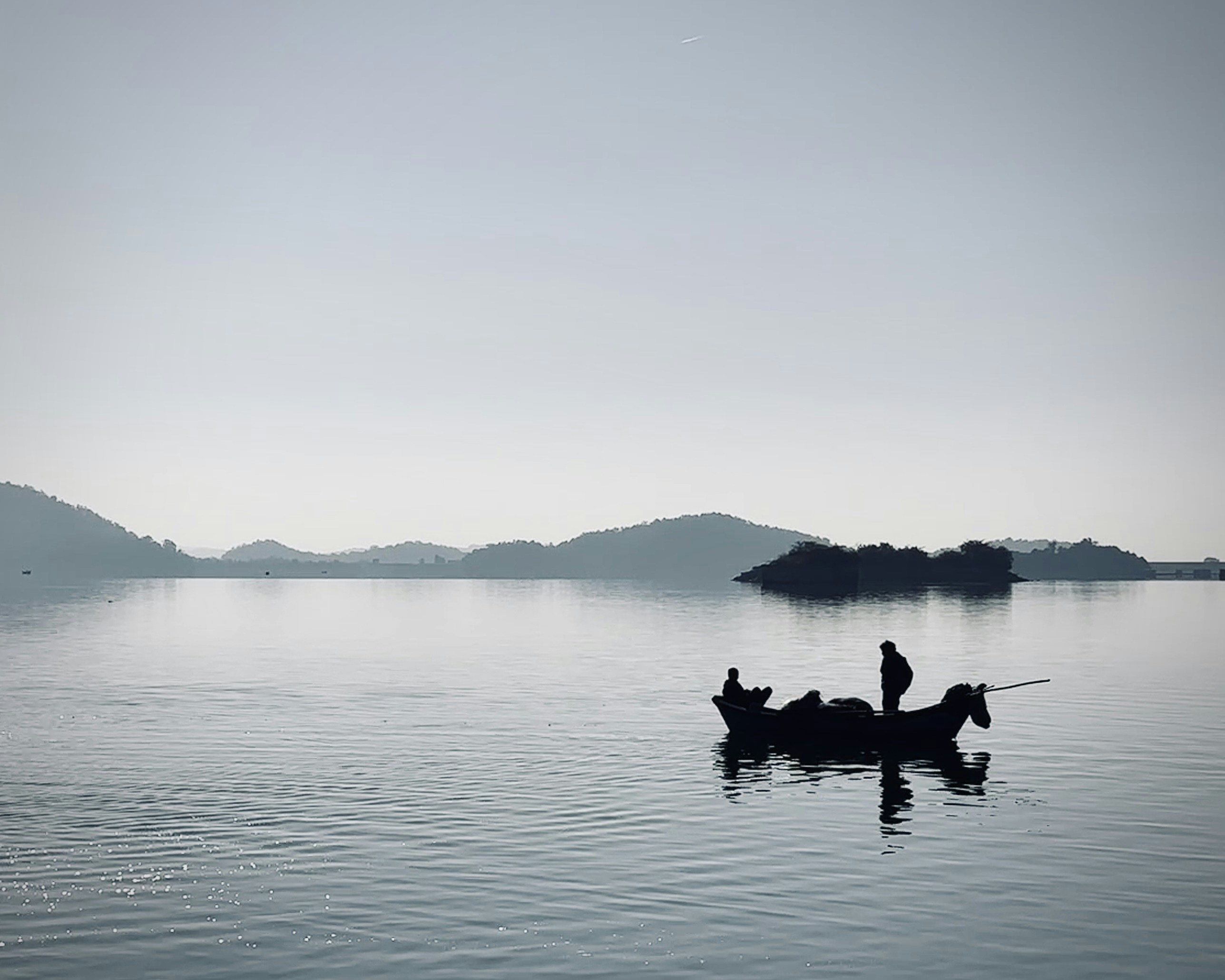 Silhouette at Sea: Boatman and Island Horizon
