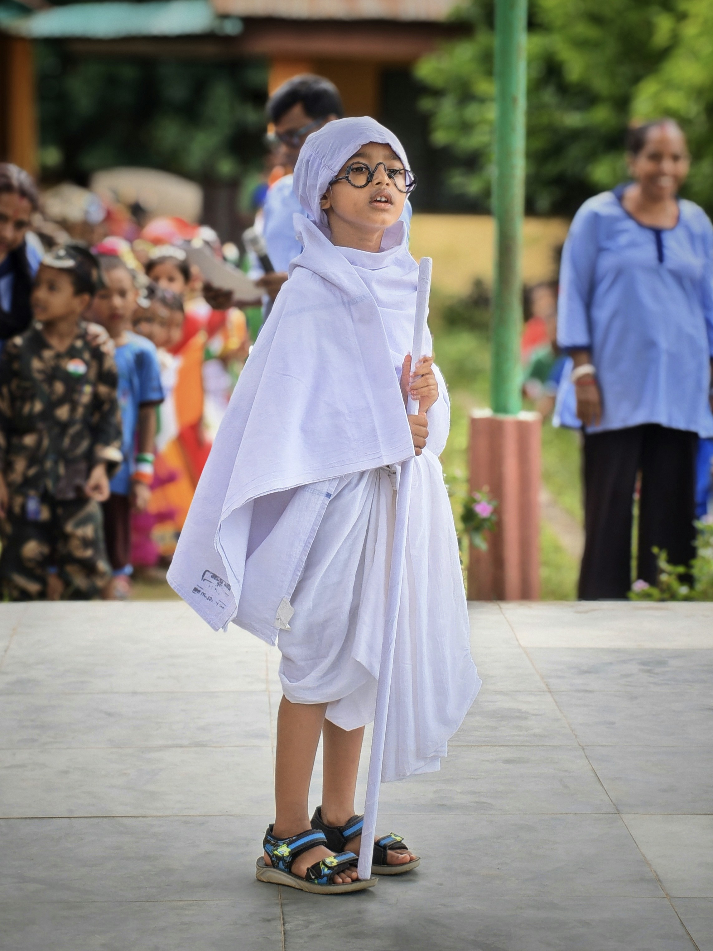 White-clad Child in Hijab Forges Focus at a Row of Onlookers