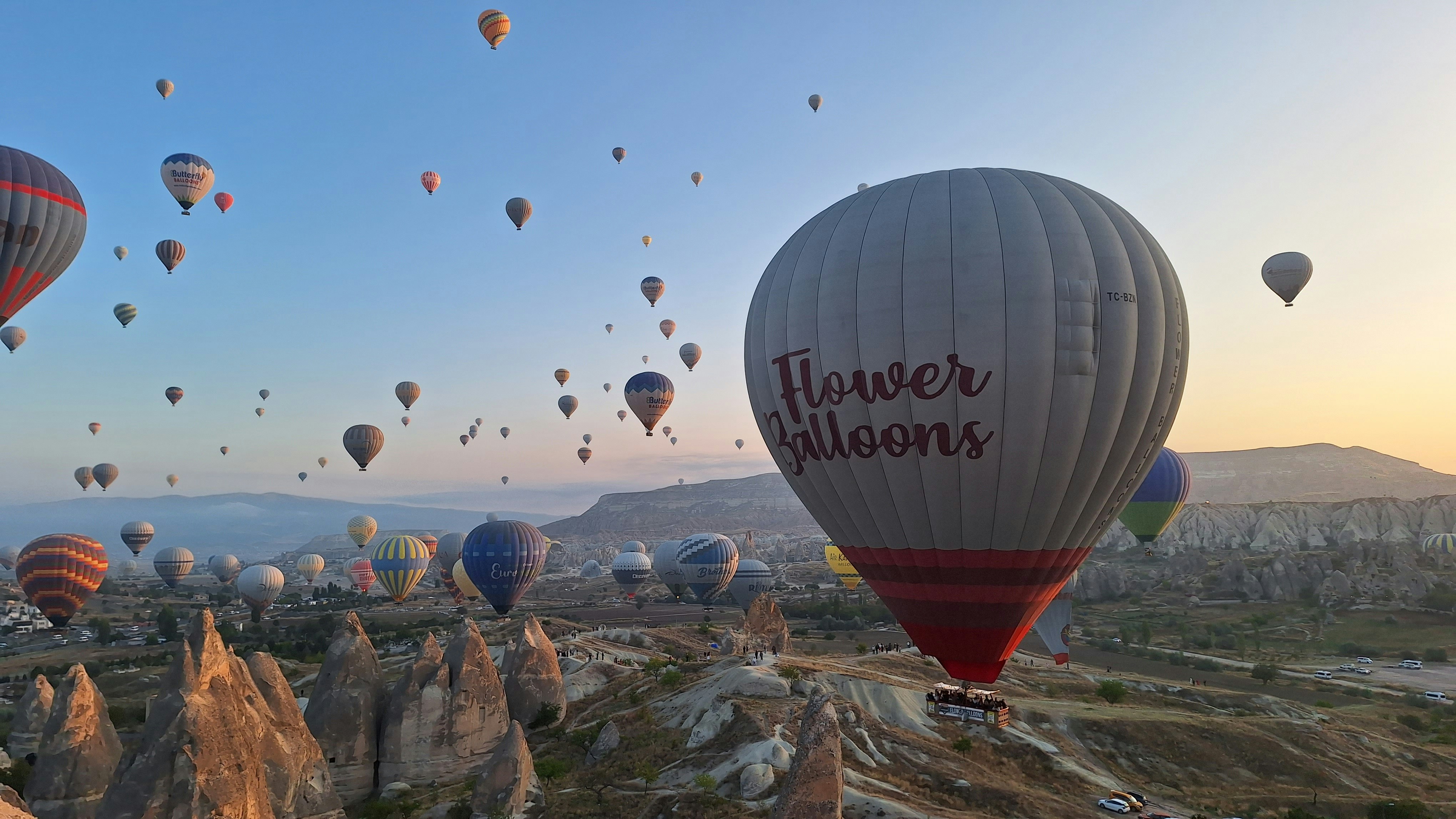 Balloon Dawn: A Sea of Rising Colors Over a Rugged Landscape