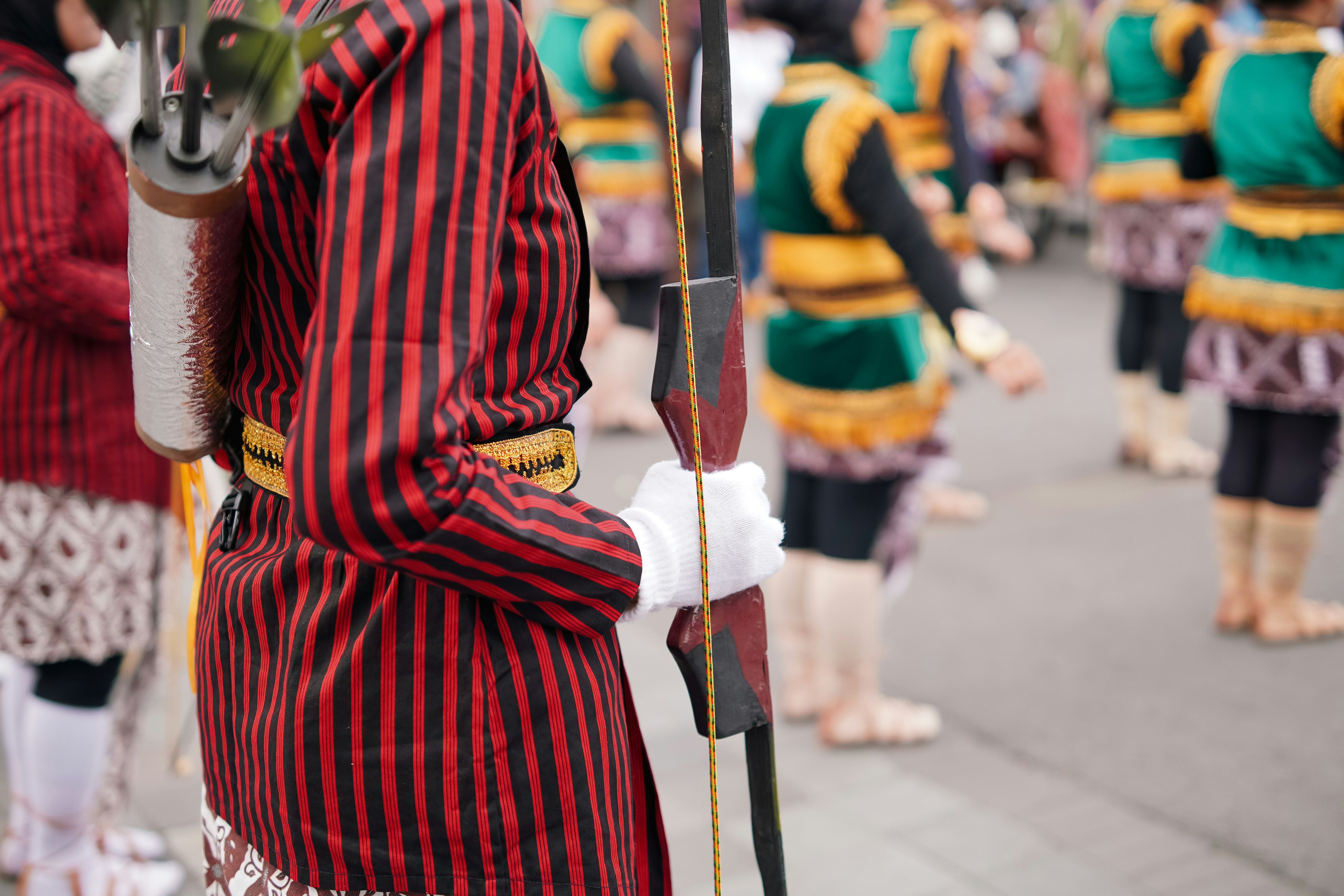 Close-up of a red-striped performer with a sword at a street parade