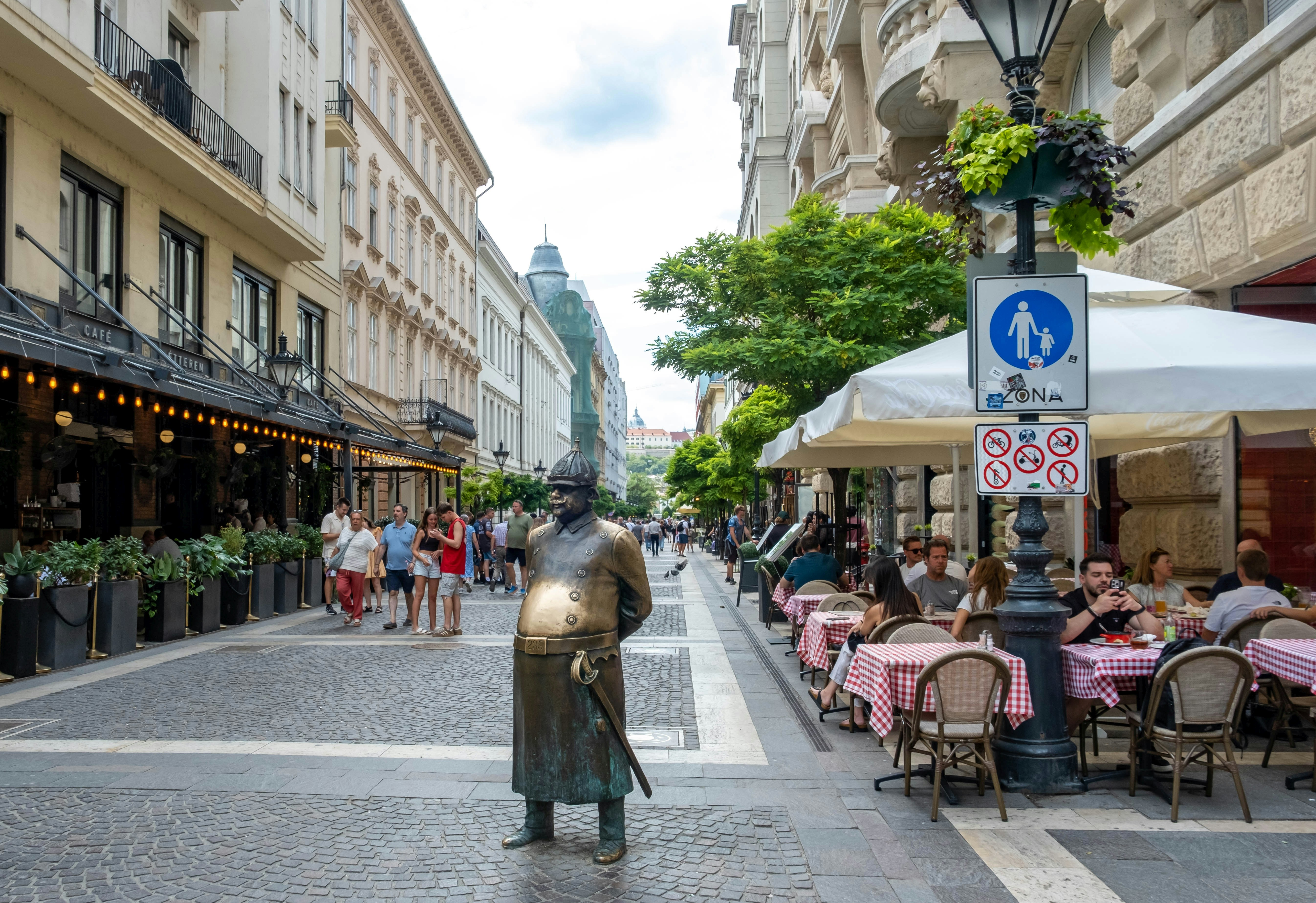 Statue sentinel watching over a lively European street cafe