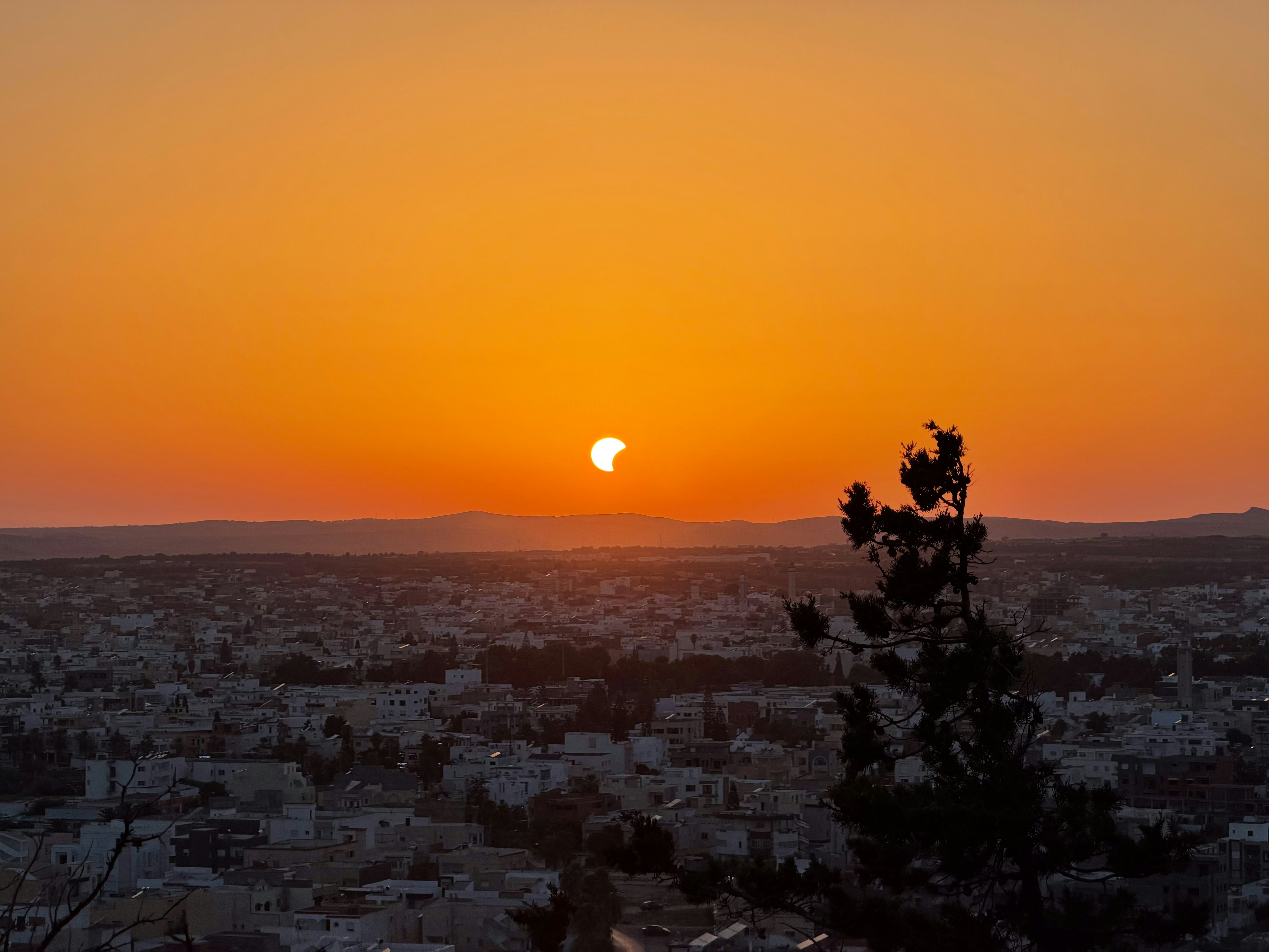 A partial solar eclipse over a sprawling city at golden hour