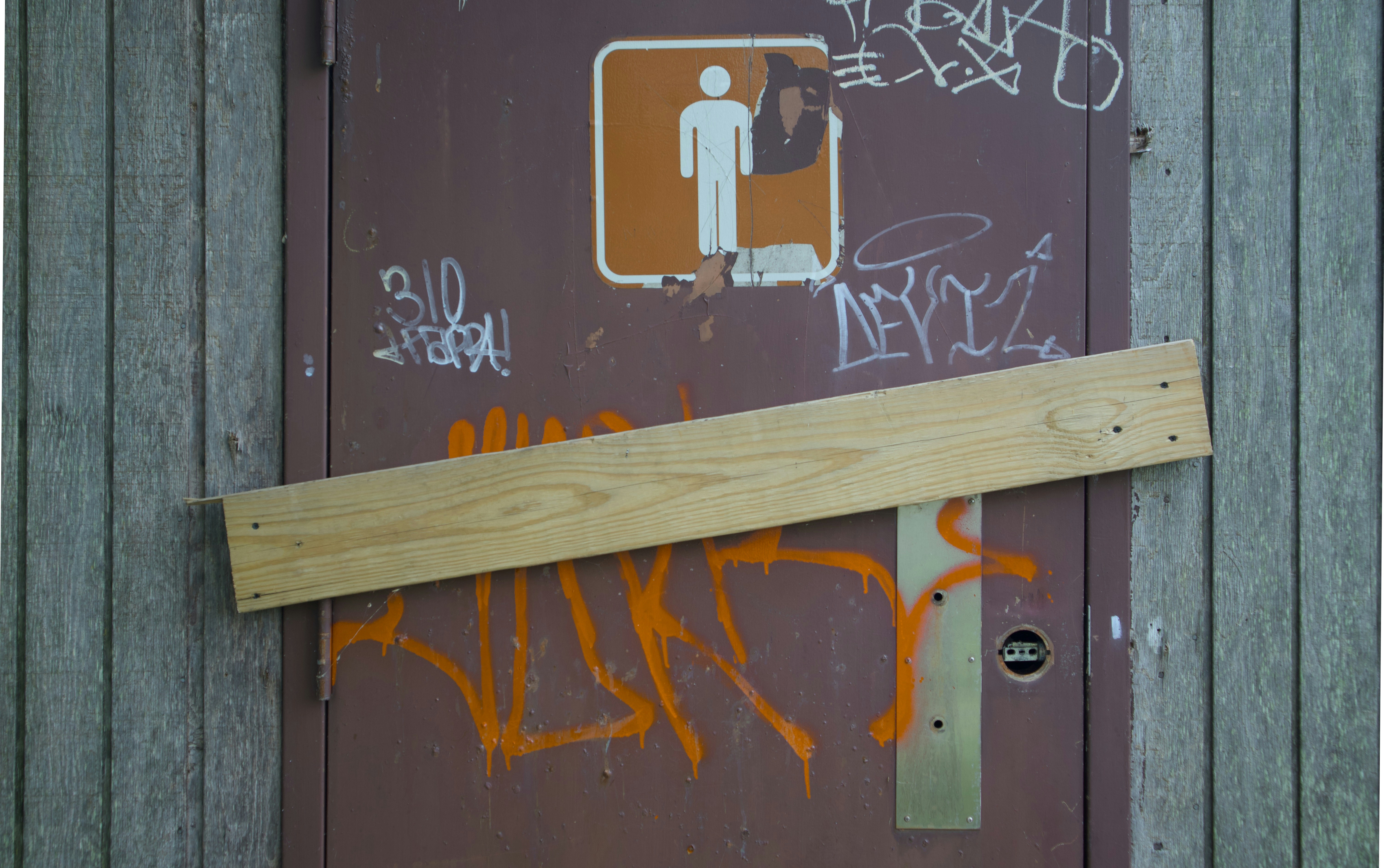 Graffiti-Tagged Door with Wooden Plank Barrier
