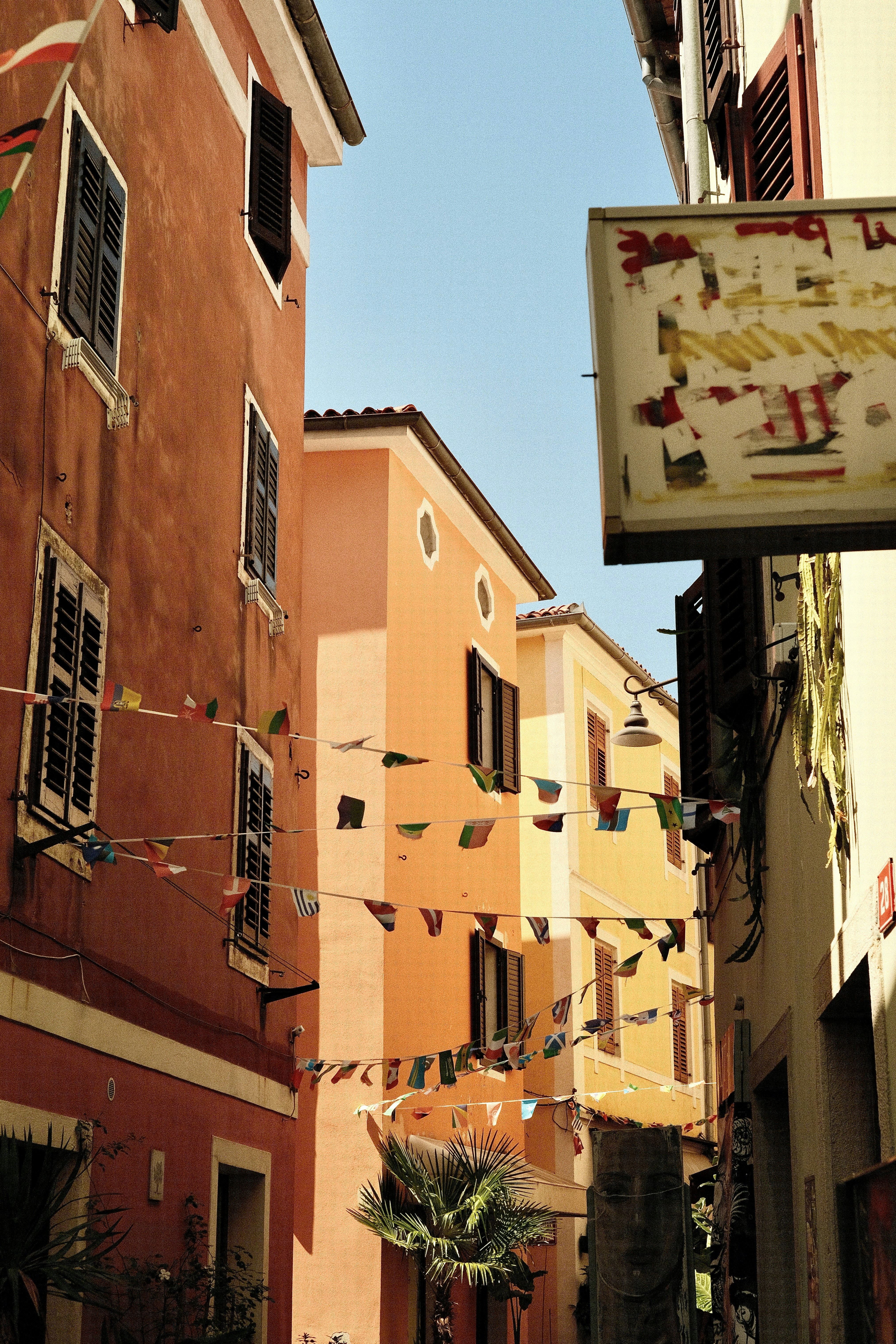 Sunlit Mediterranean Lane with Colorful Facades and Festive Bunting