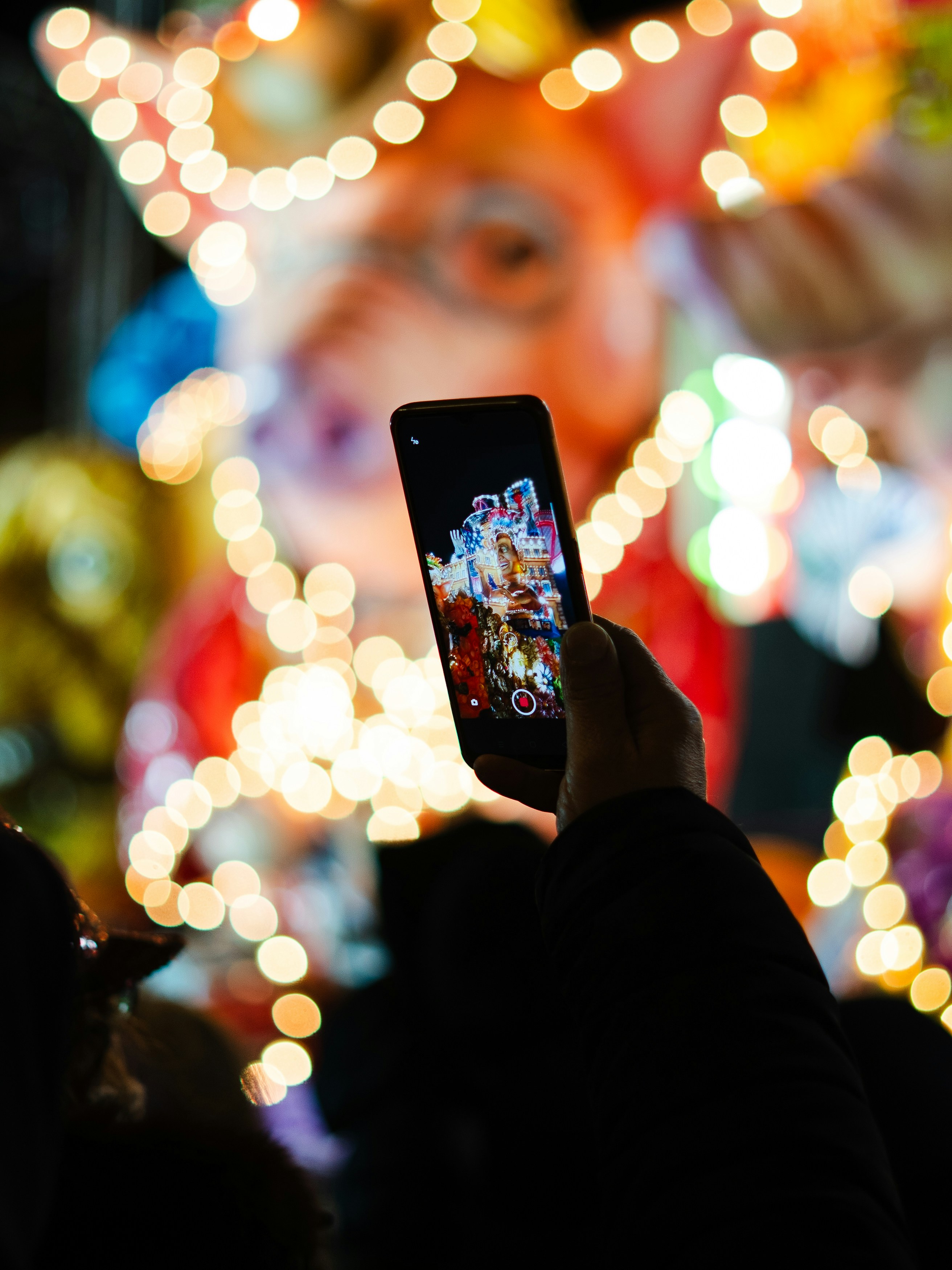 Midnight Portrait: A Glowing Smartphone Silhouette in a Carnival Pillow of Lights