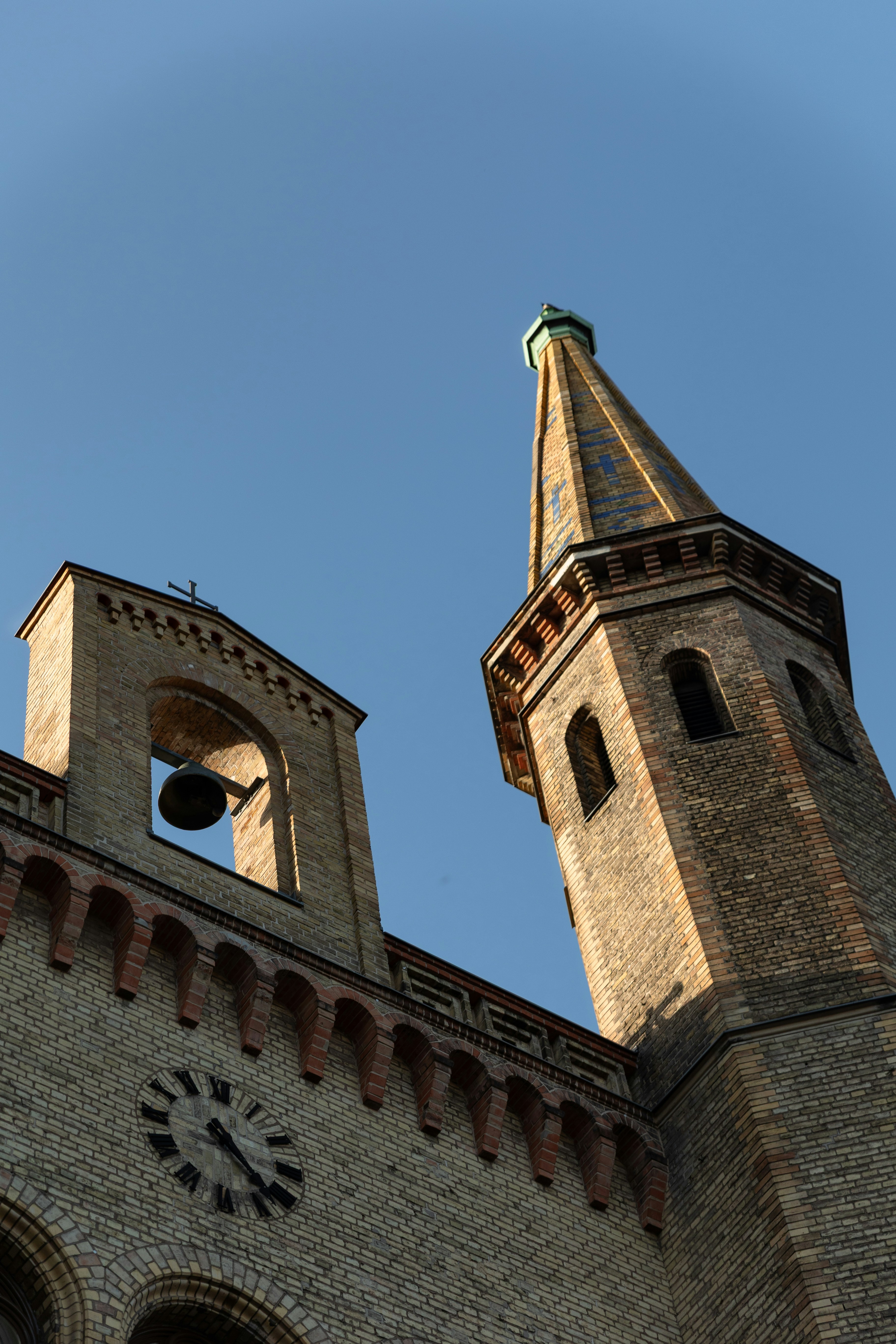 Brick Spire Reach: A Low-Aangle View of a Historic Church Tower Against a Clear Sky