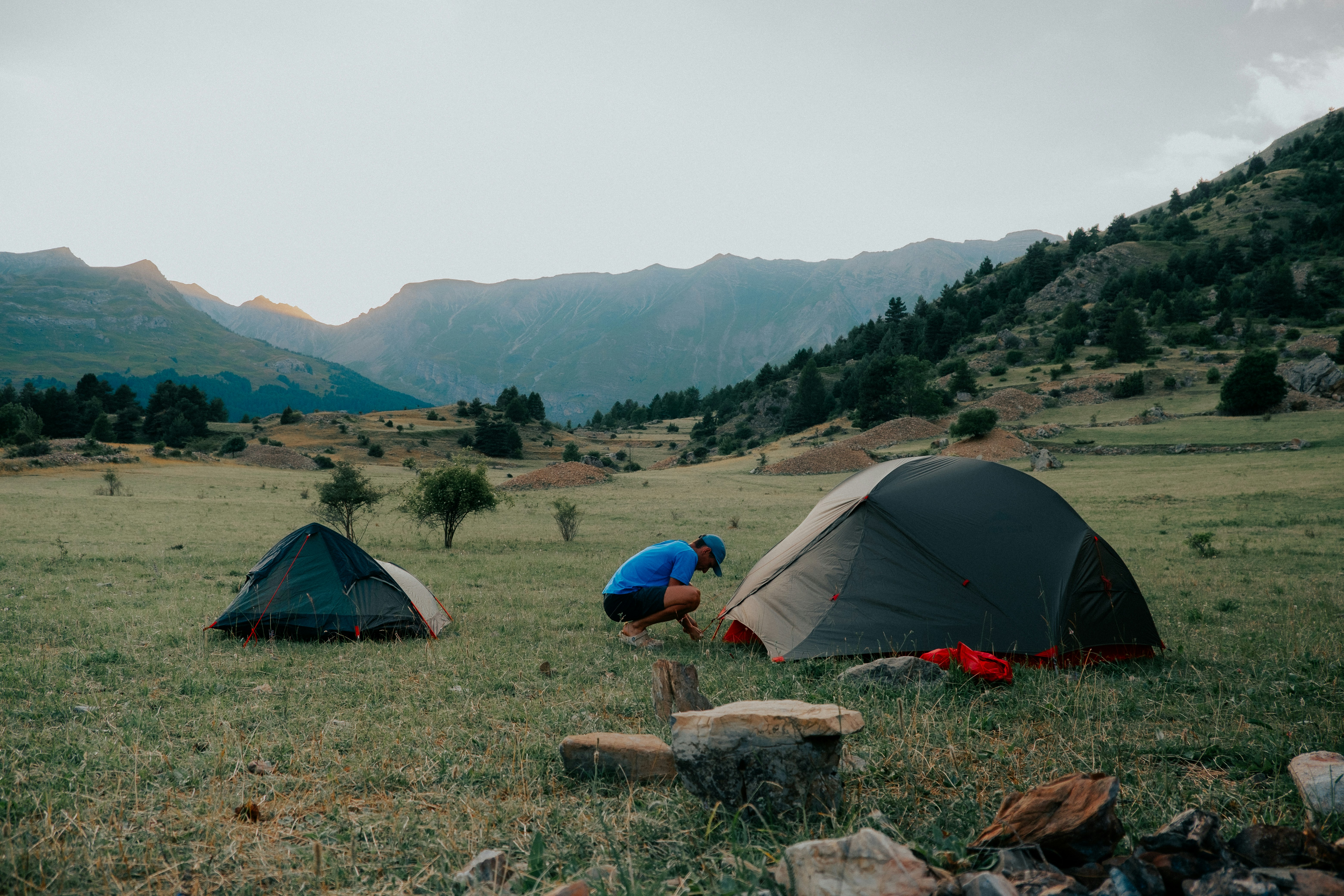 Blue Shirt, Red Tent: A Campsite Against Mountain Pastures