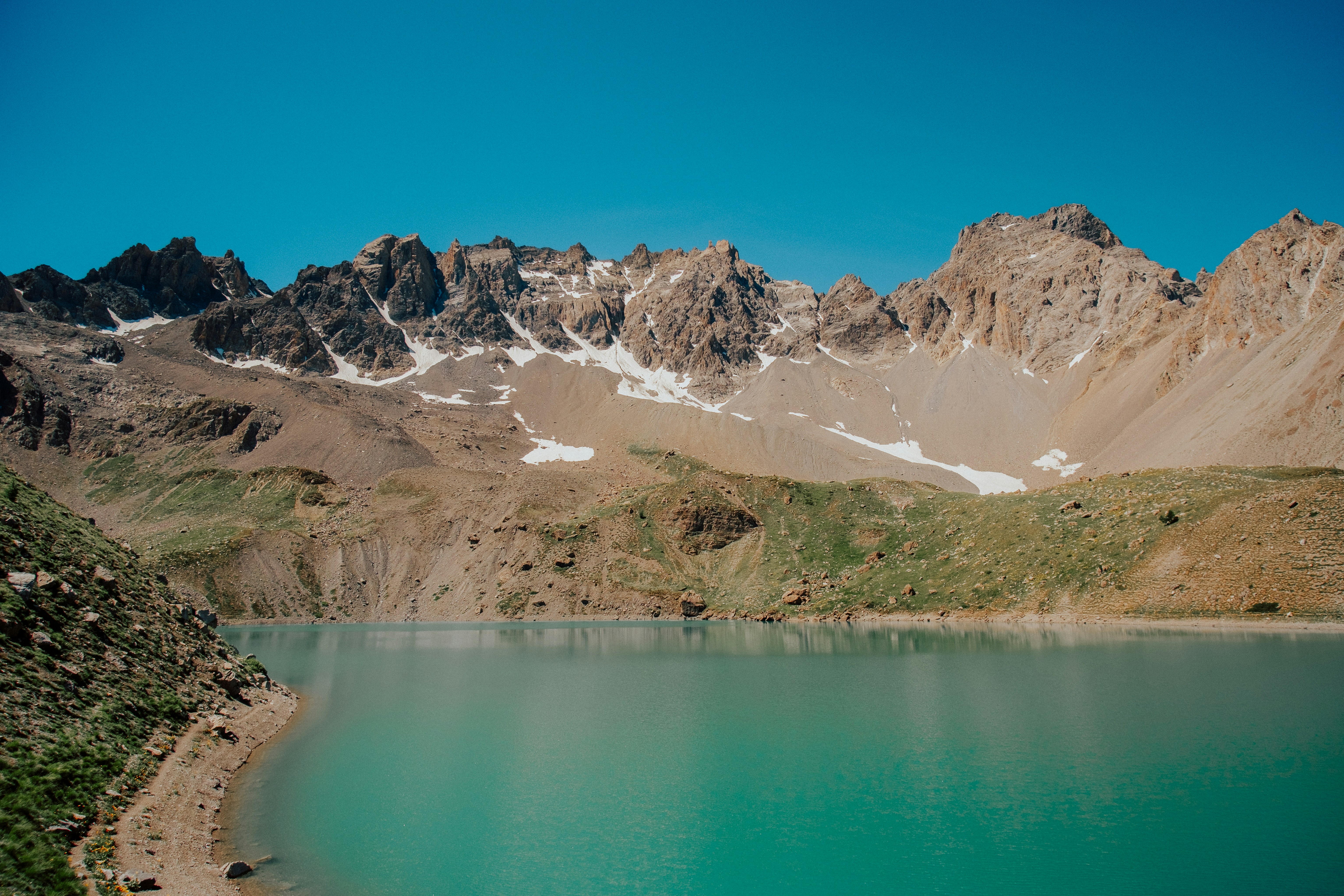 Turquoise Lake at the Foot of Rugged Snow-dusted Peaks