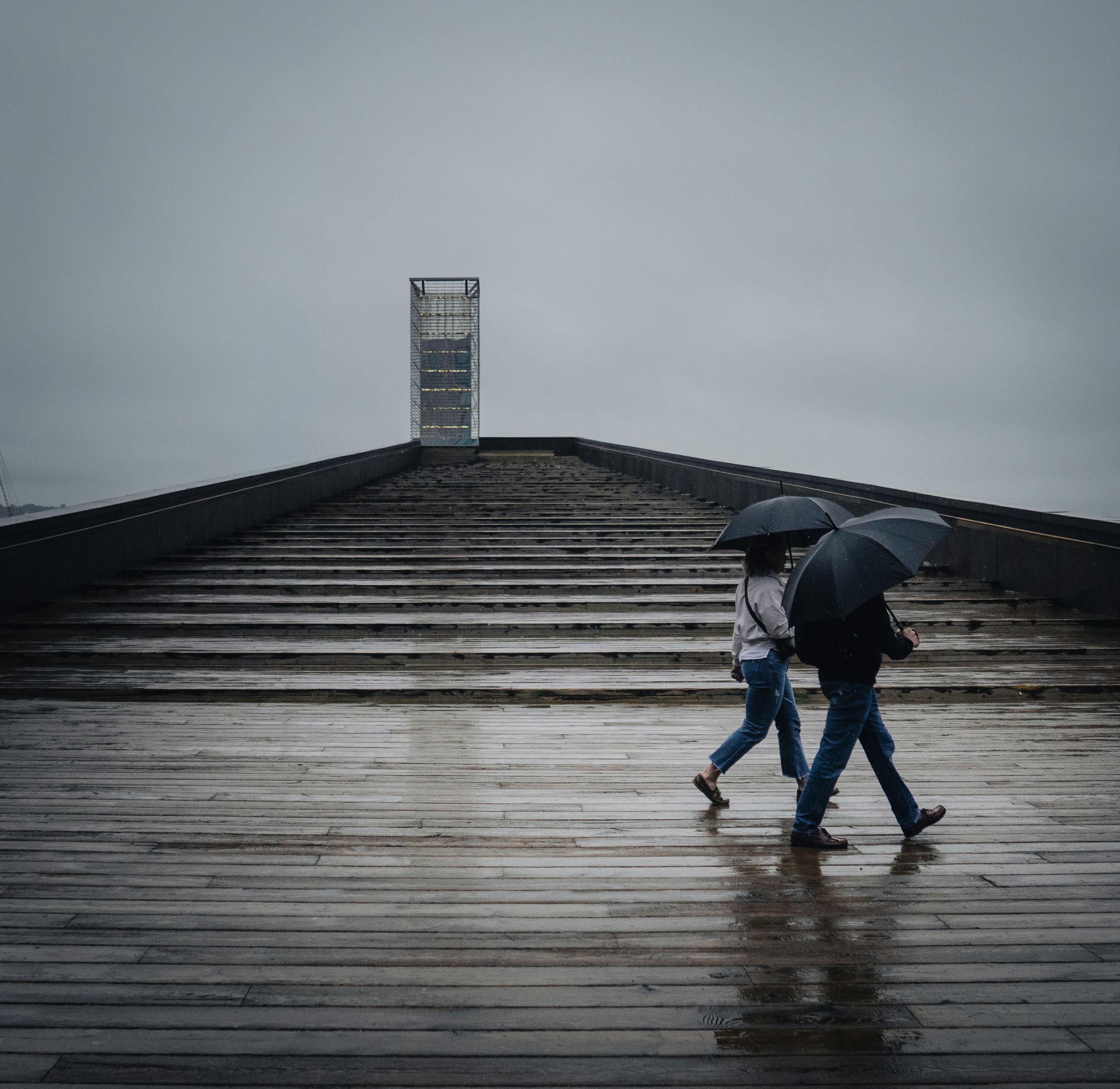 Along the Wet Ridge: Two Figures under Dark Skies on a Rooftop