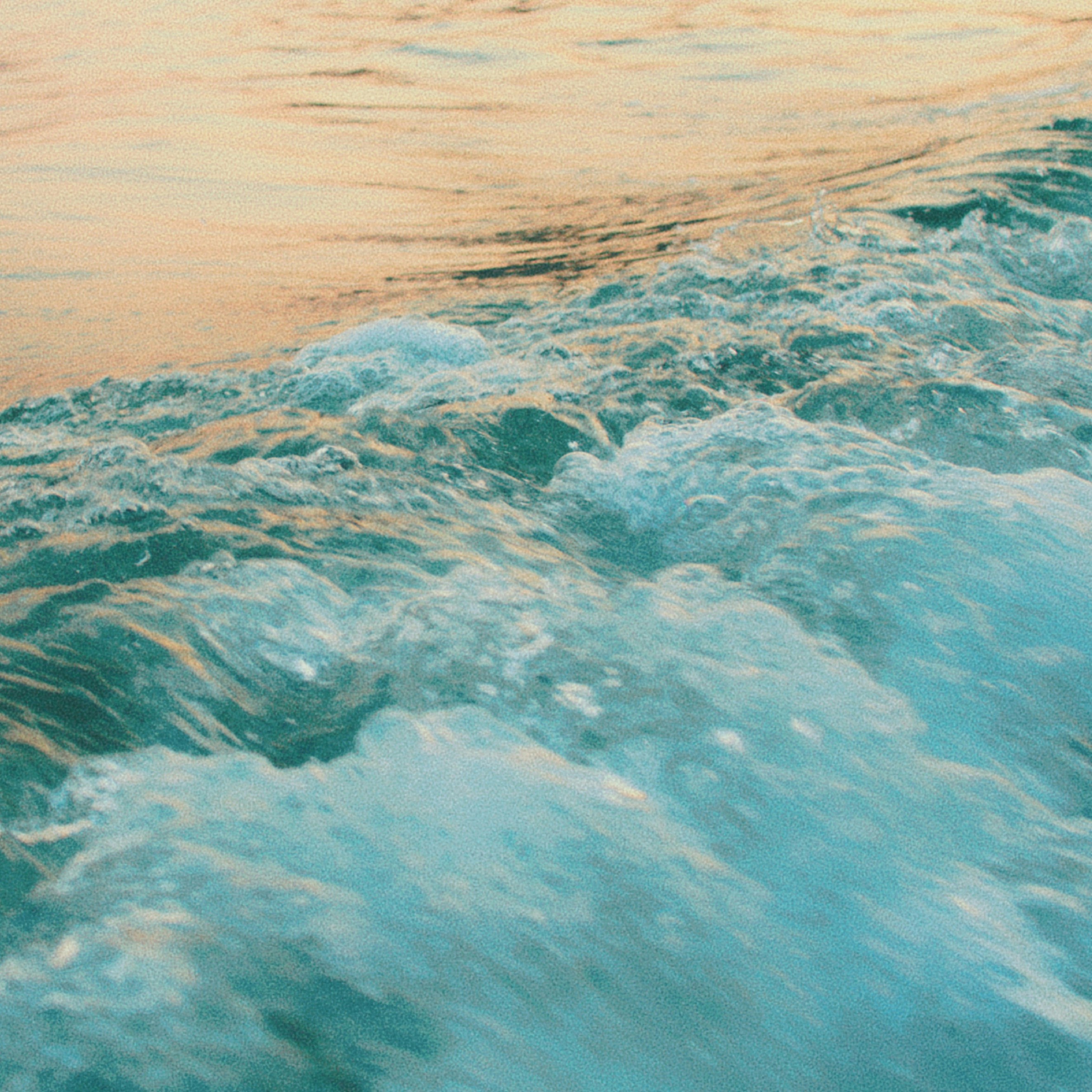 Swirling turquoise waves crest under a warm sky, capturing motion and texture in a seascape with dynamic light.