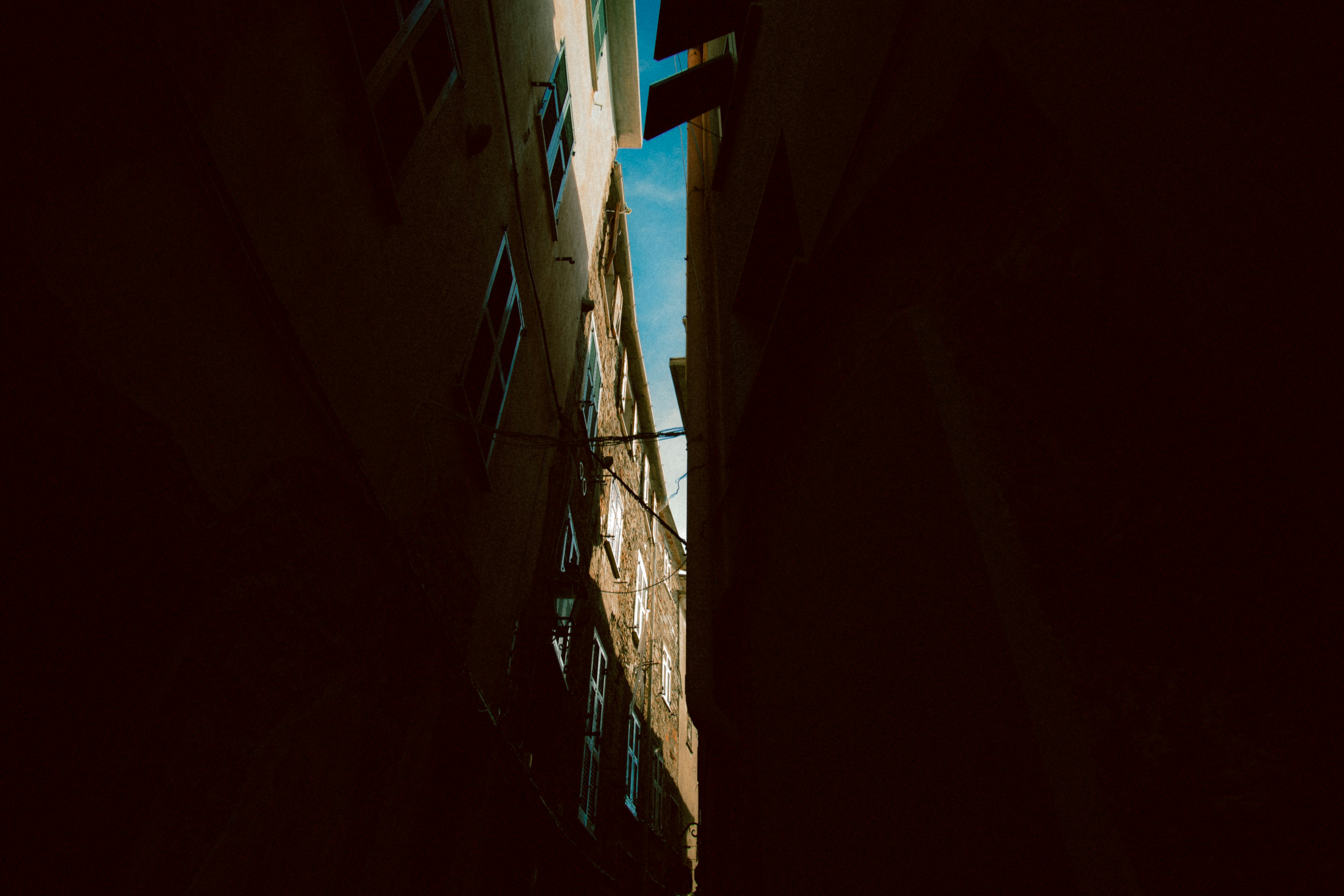 Narrow Skyward Gap: Sunlit Facades Between Shadows