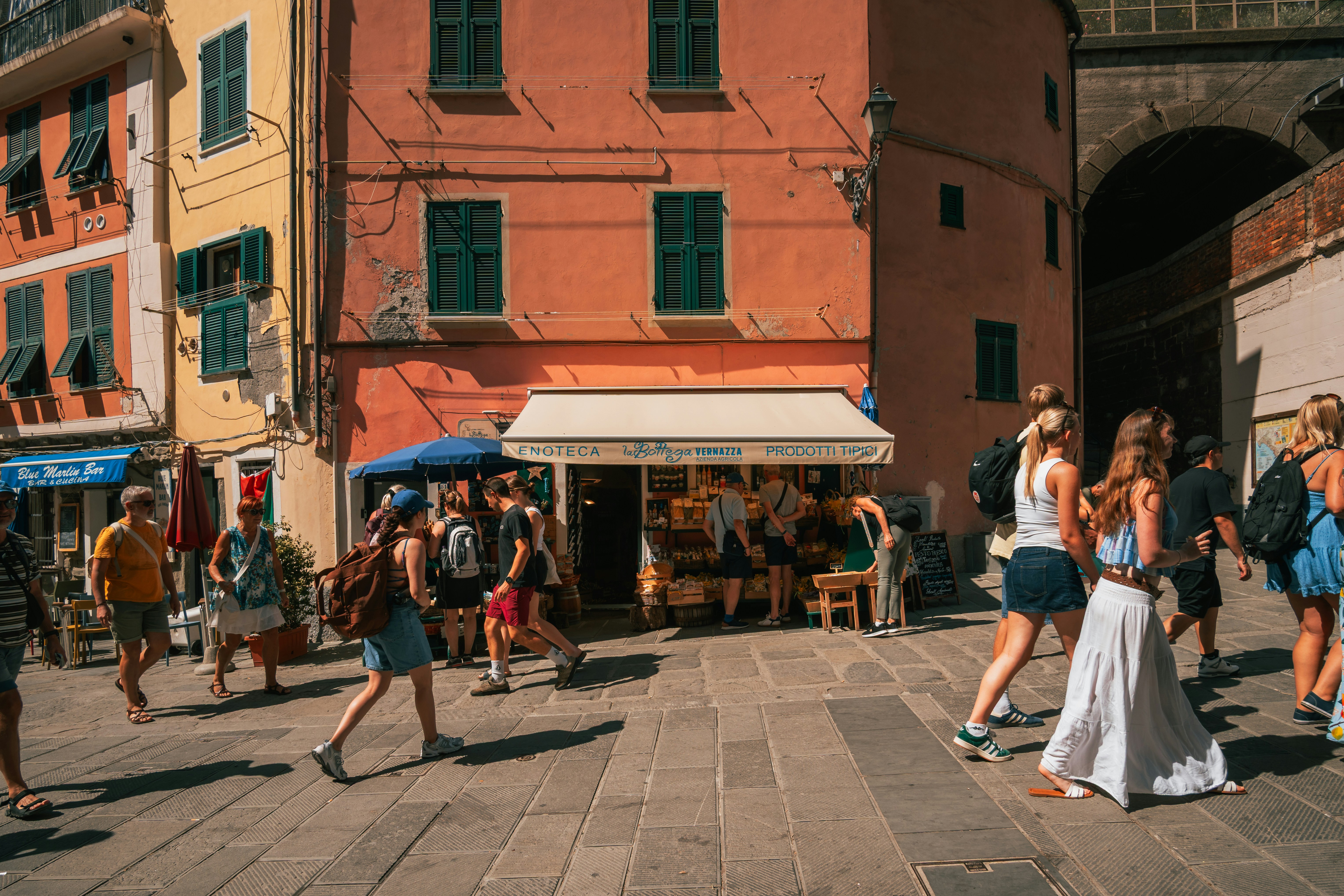 Sunlit Piazza Snapshot: A Colorful Corridor of People and Olive-Windowed Facades