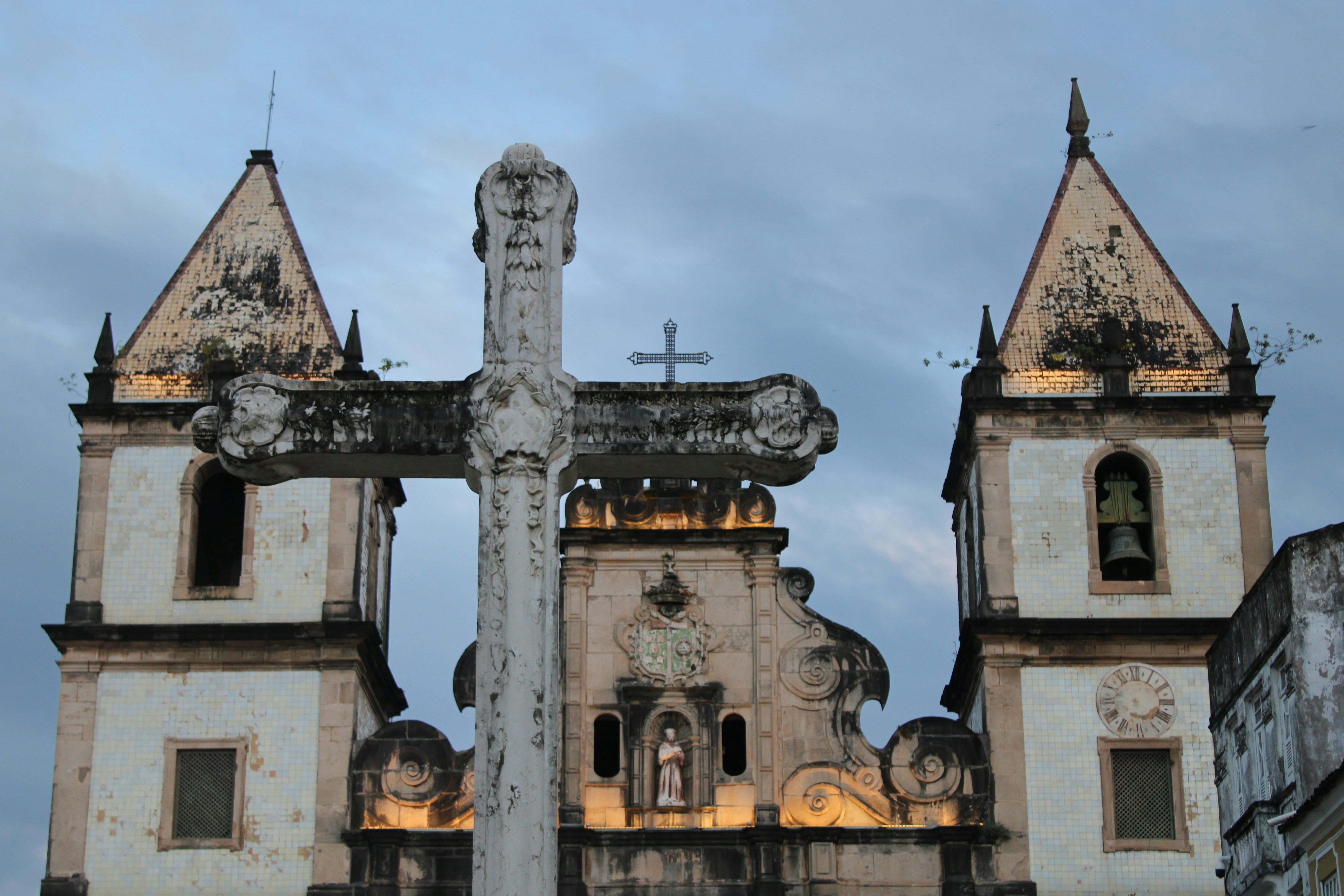 Weathered Cross and Twin Bell Towers Framing a Dusk-Softened Cathedral