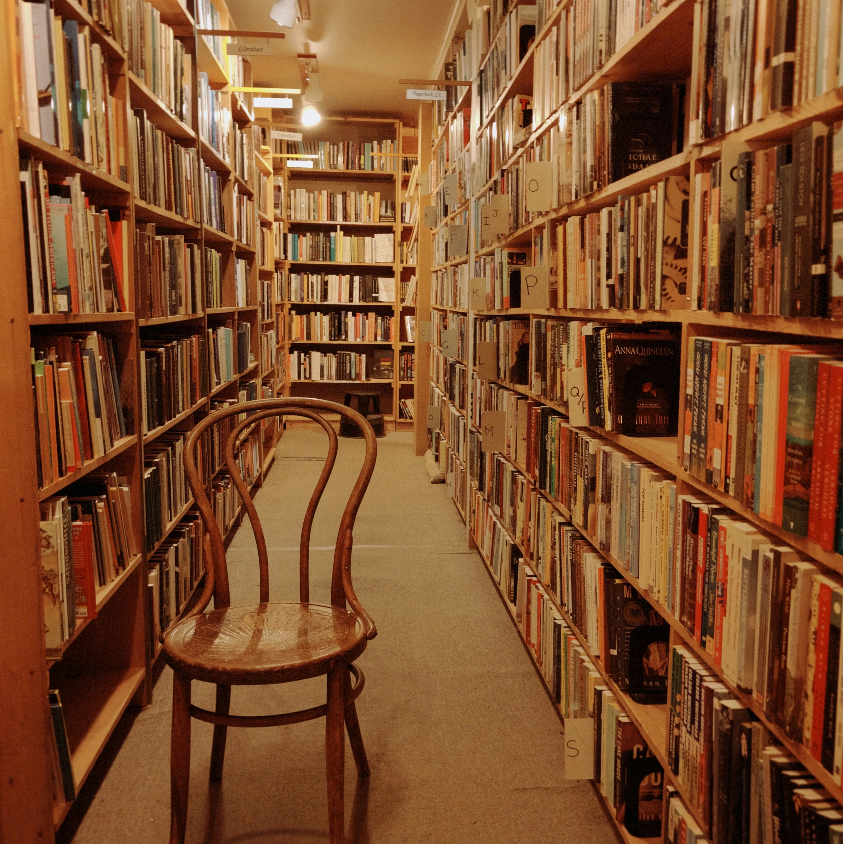 A Quiet Aisle: Wooden Shelves and a Single Stool in a Warm Library