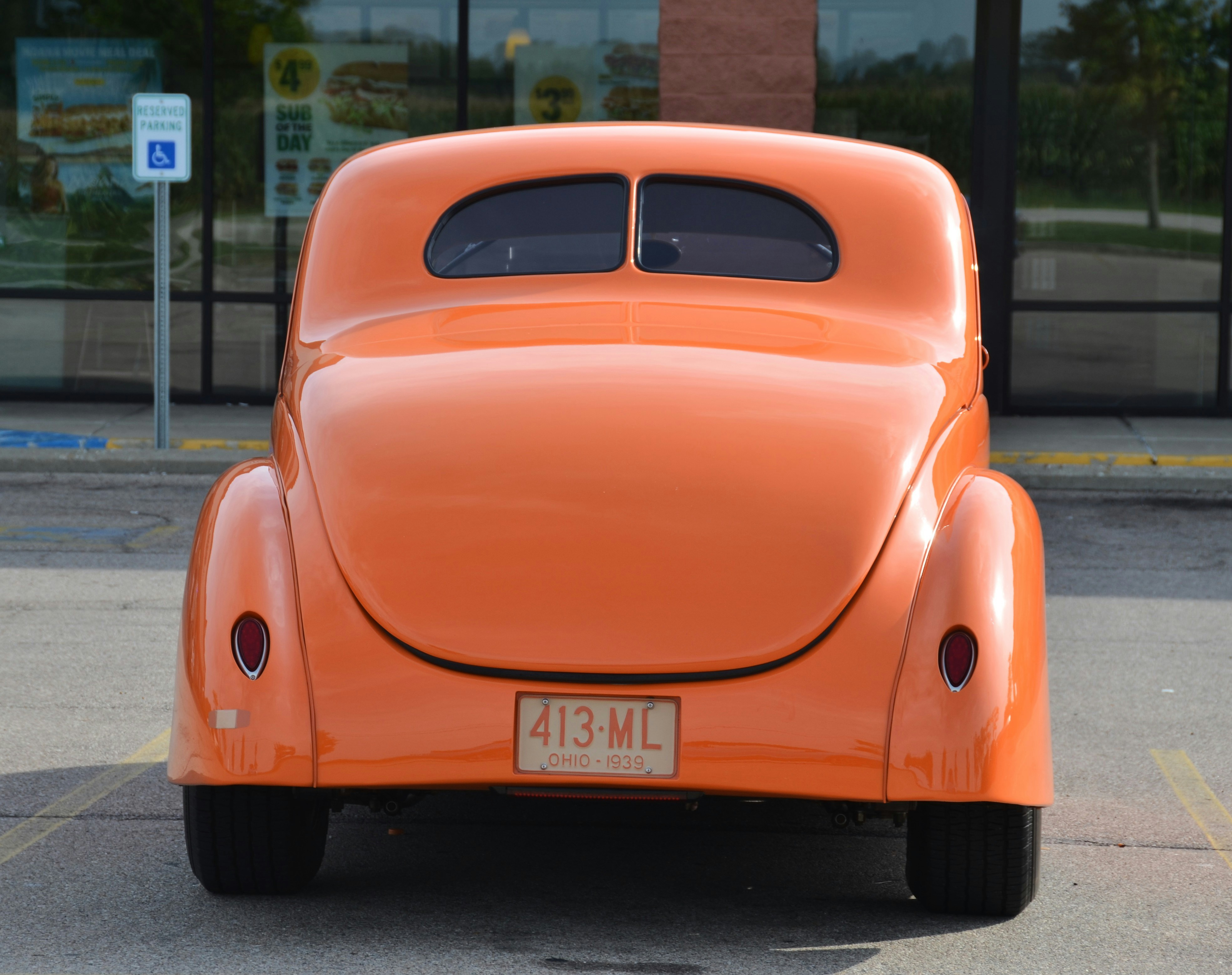 Orange vintage sedan from the rear, parked in a lot