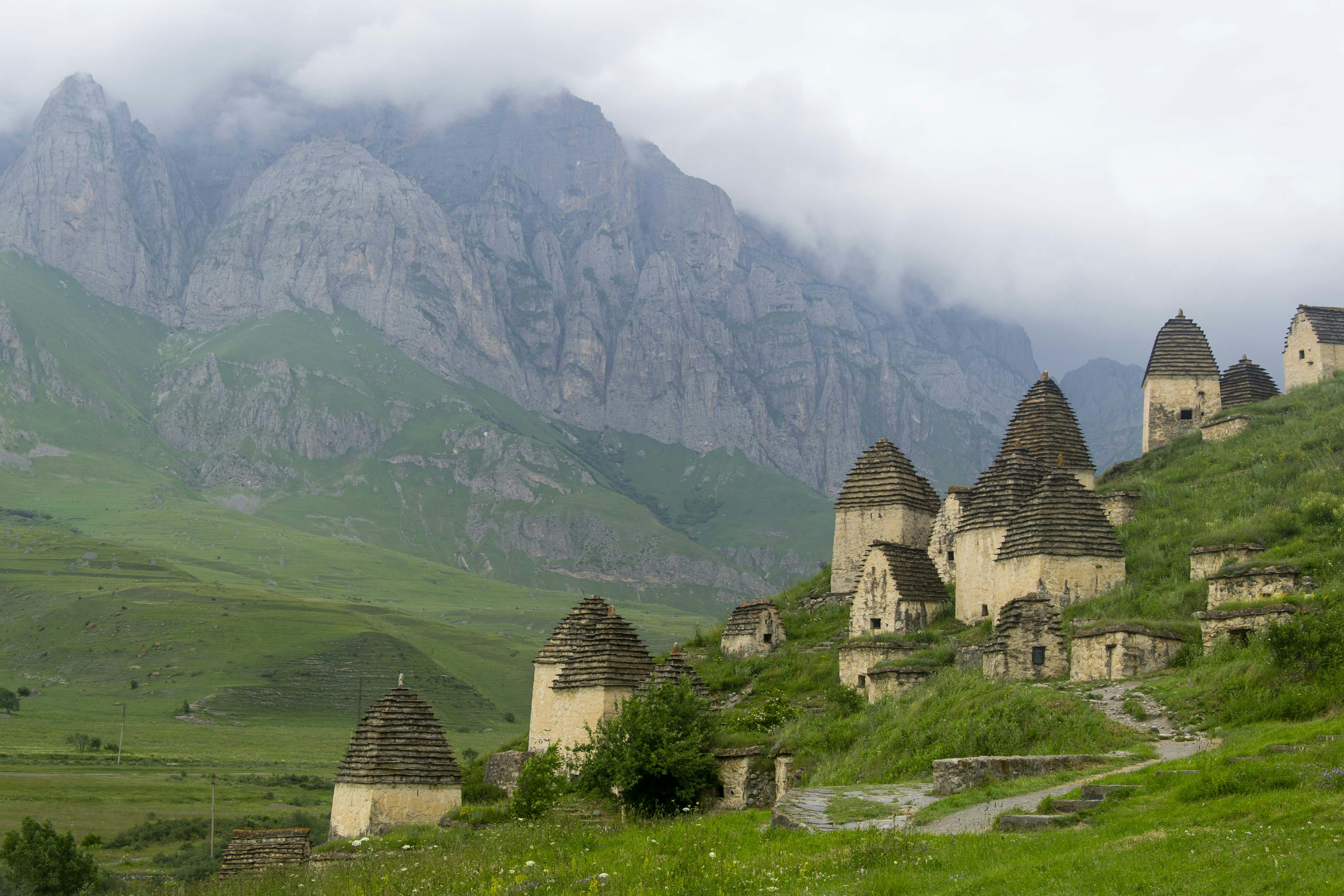 Stone Beacons on a Green Slope under Misty Peaks