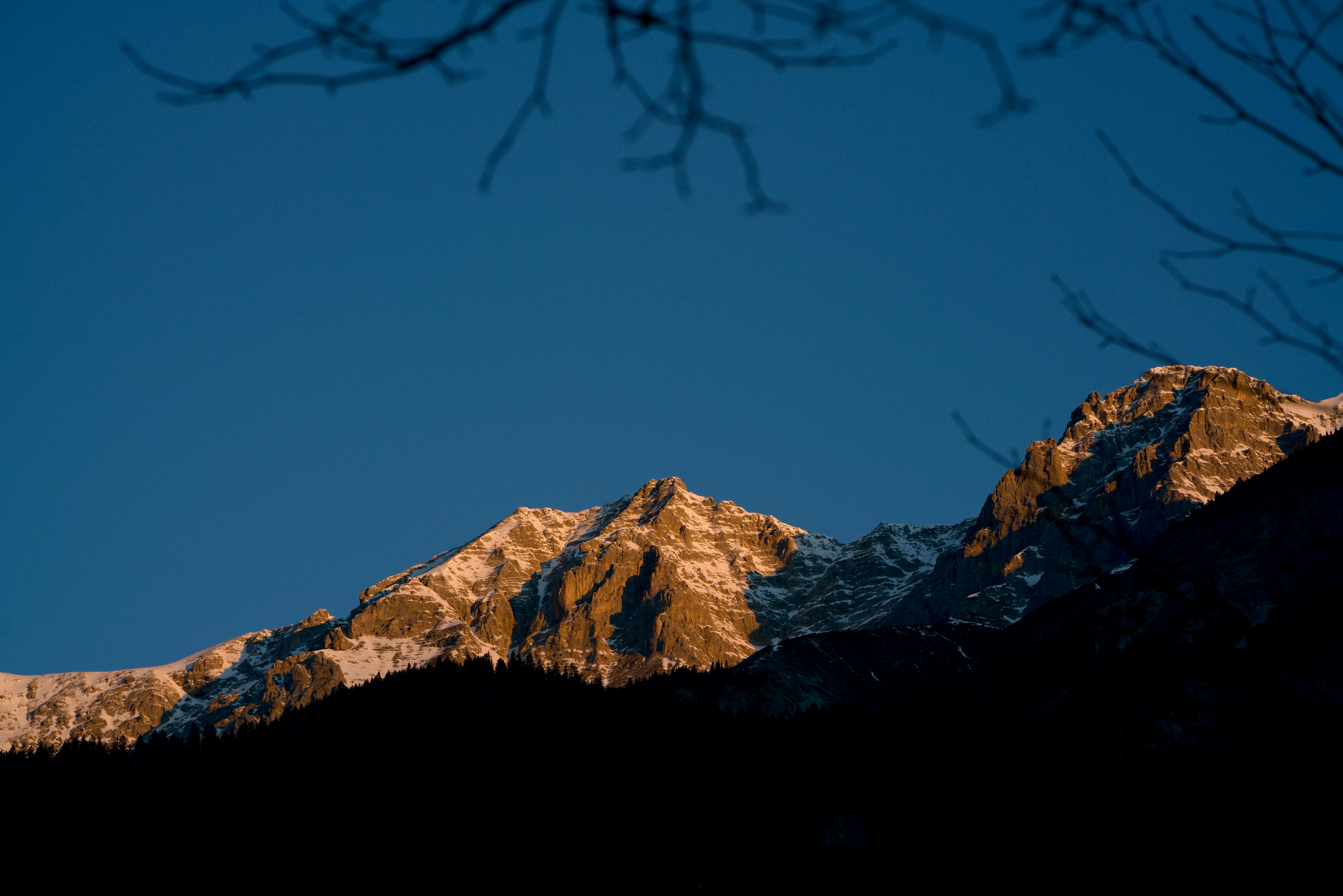 Golden Peaks at Dusk: Snow-Capped Crown Elevates a Dark Horizon