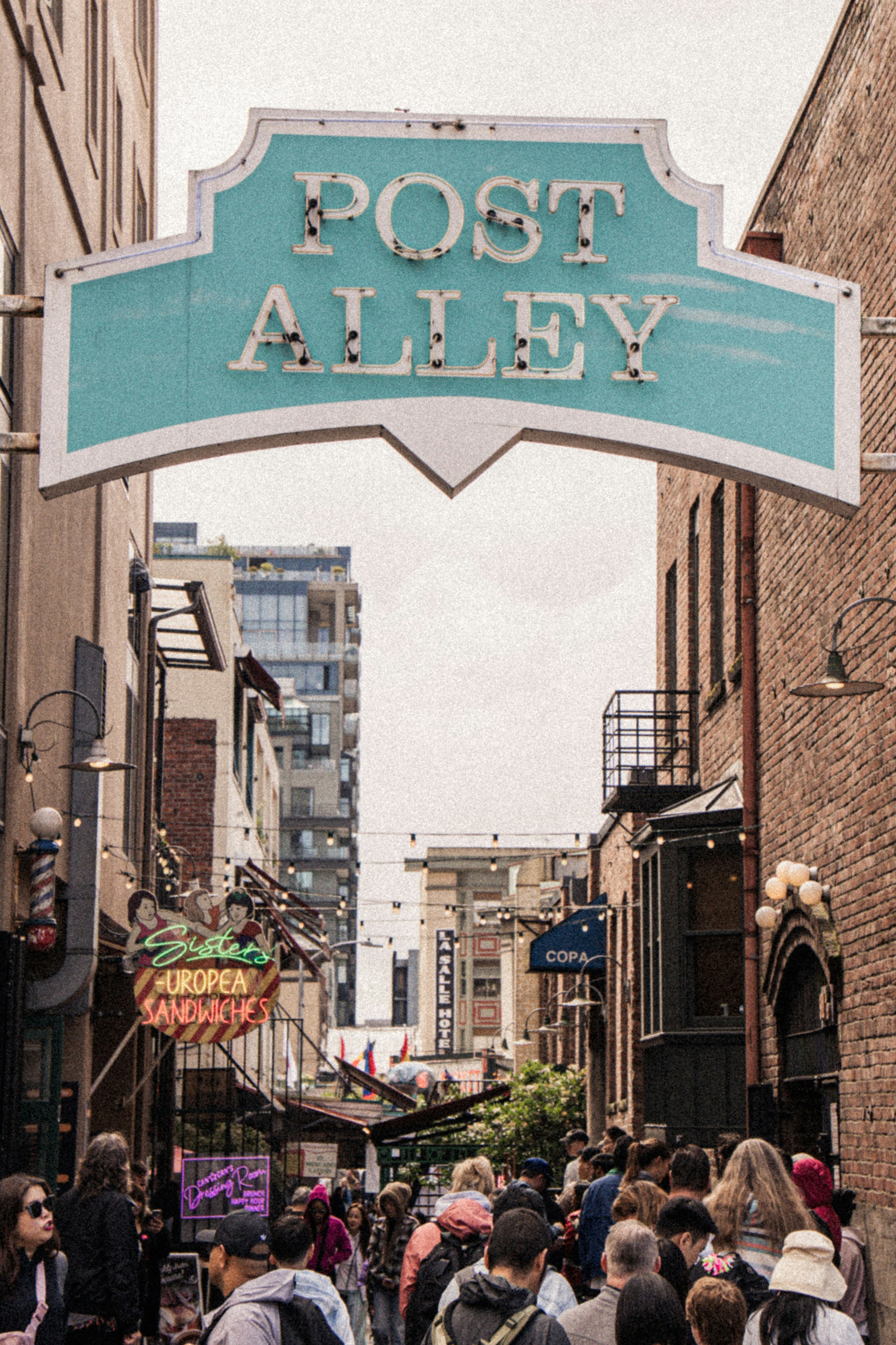 Post Alley Gateway: A Lively Urban Corridor Beneath a Vintage Sign