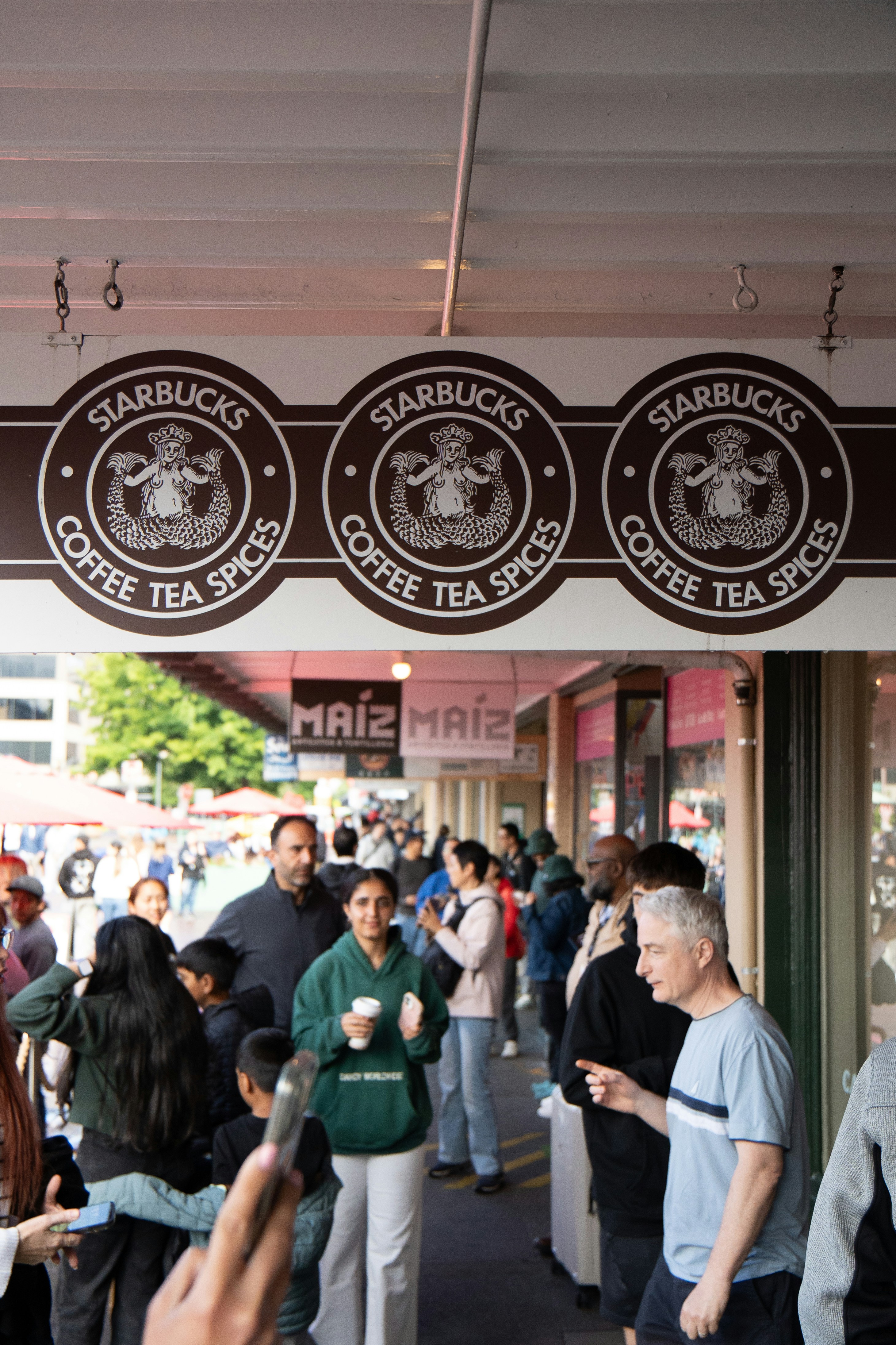 Street Scene under Starbucks Signage: Crowd of People with a Green Hoodie Center Stage