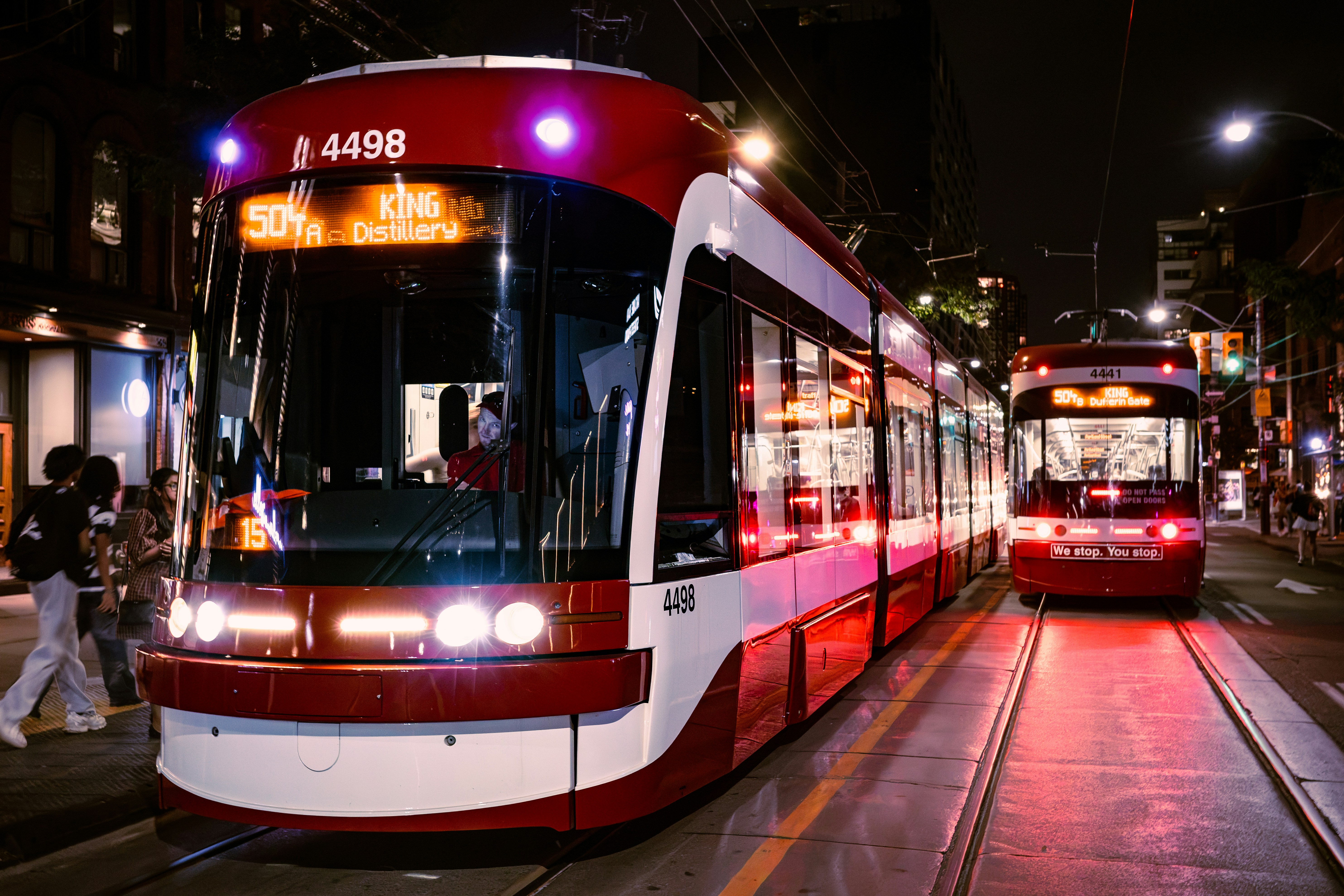 Night Pulse: Red and White Trams Gliding Past a City Street