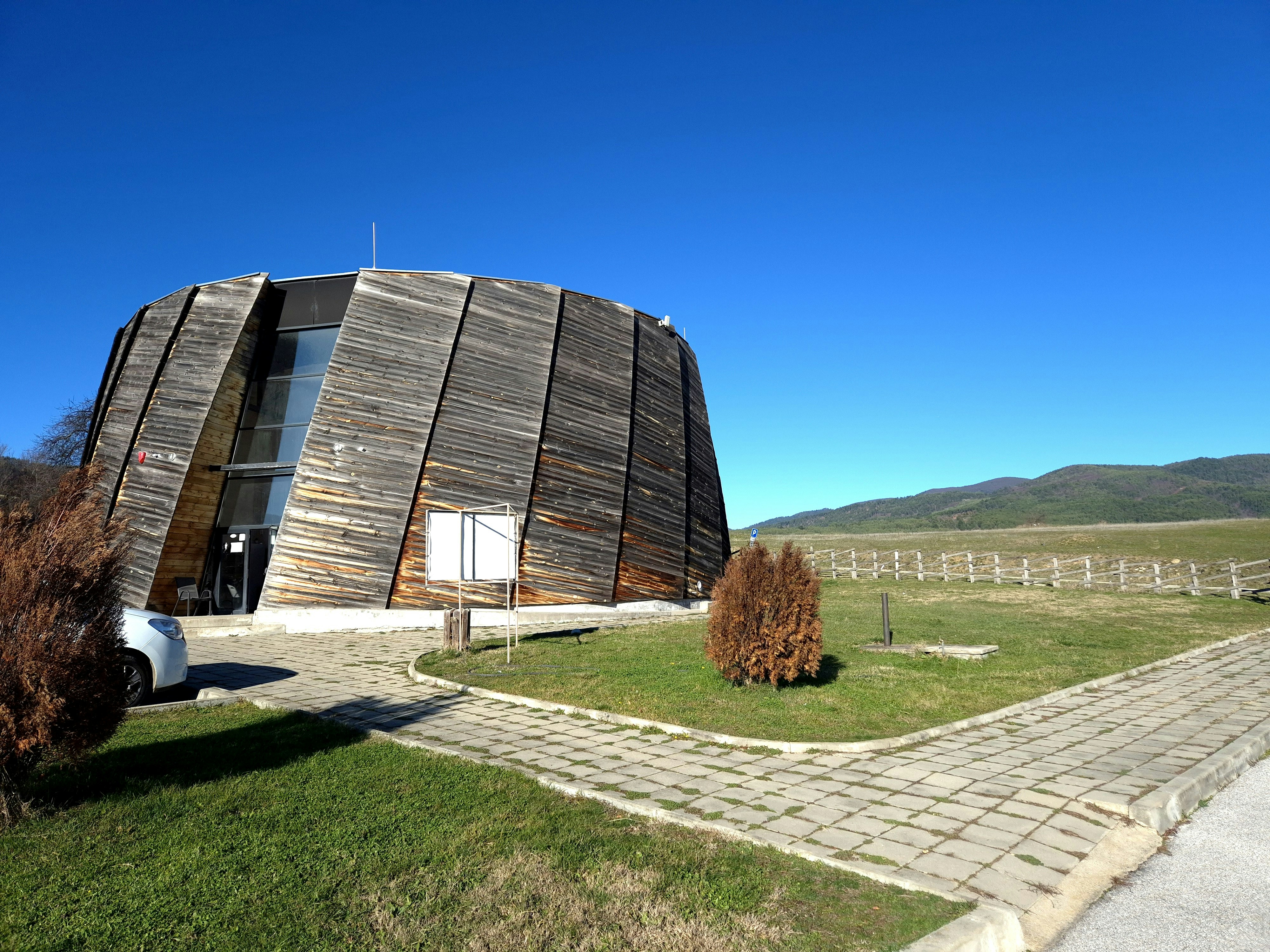 Curved wooden observatory under a clear blue sky