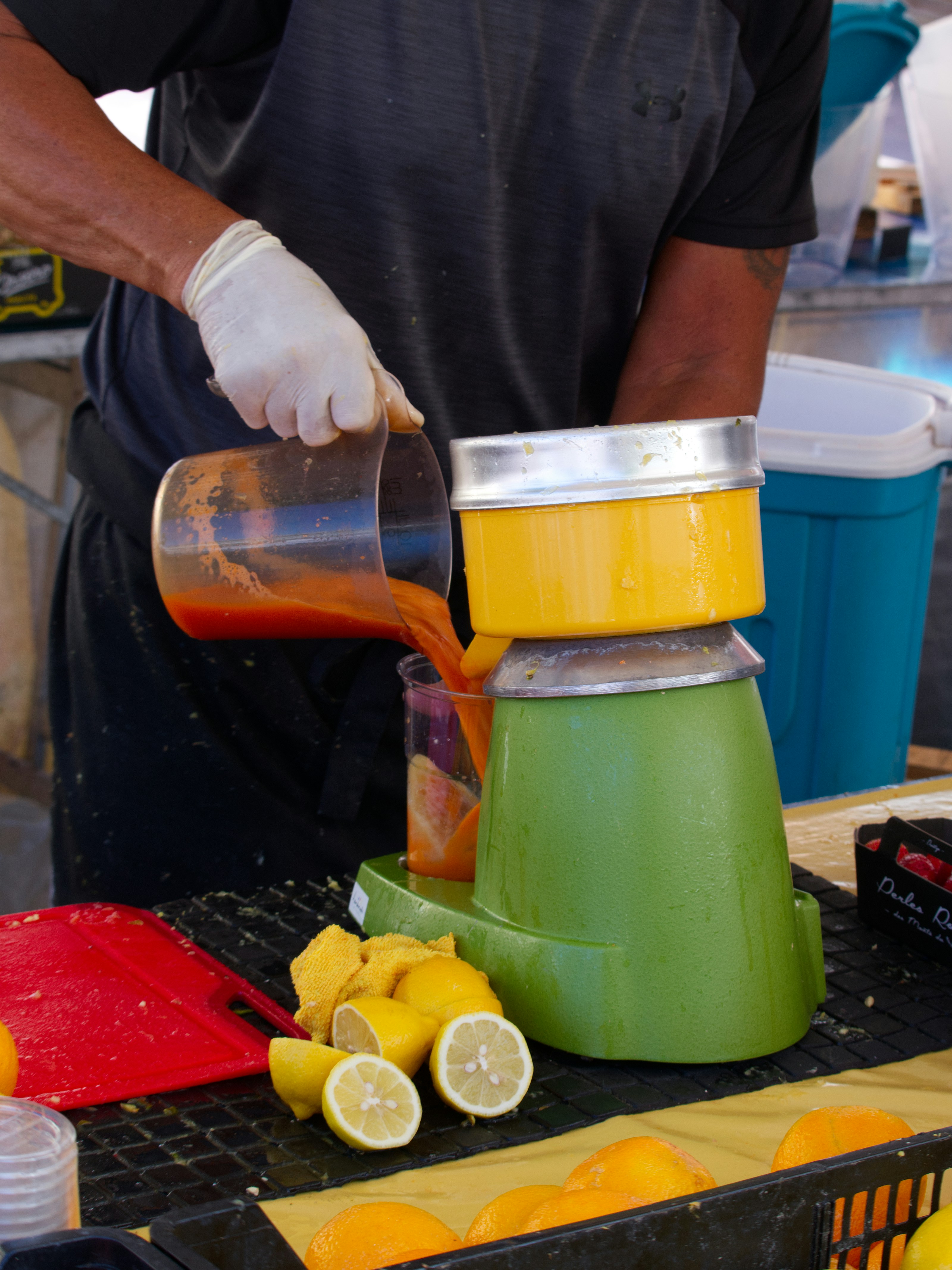 A person in a black shirt pouring orange juice into a plastic cup
