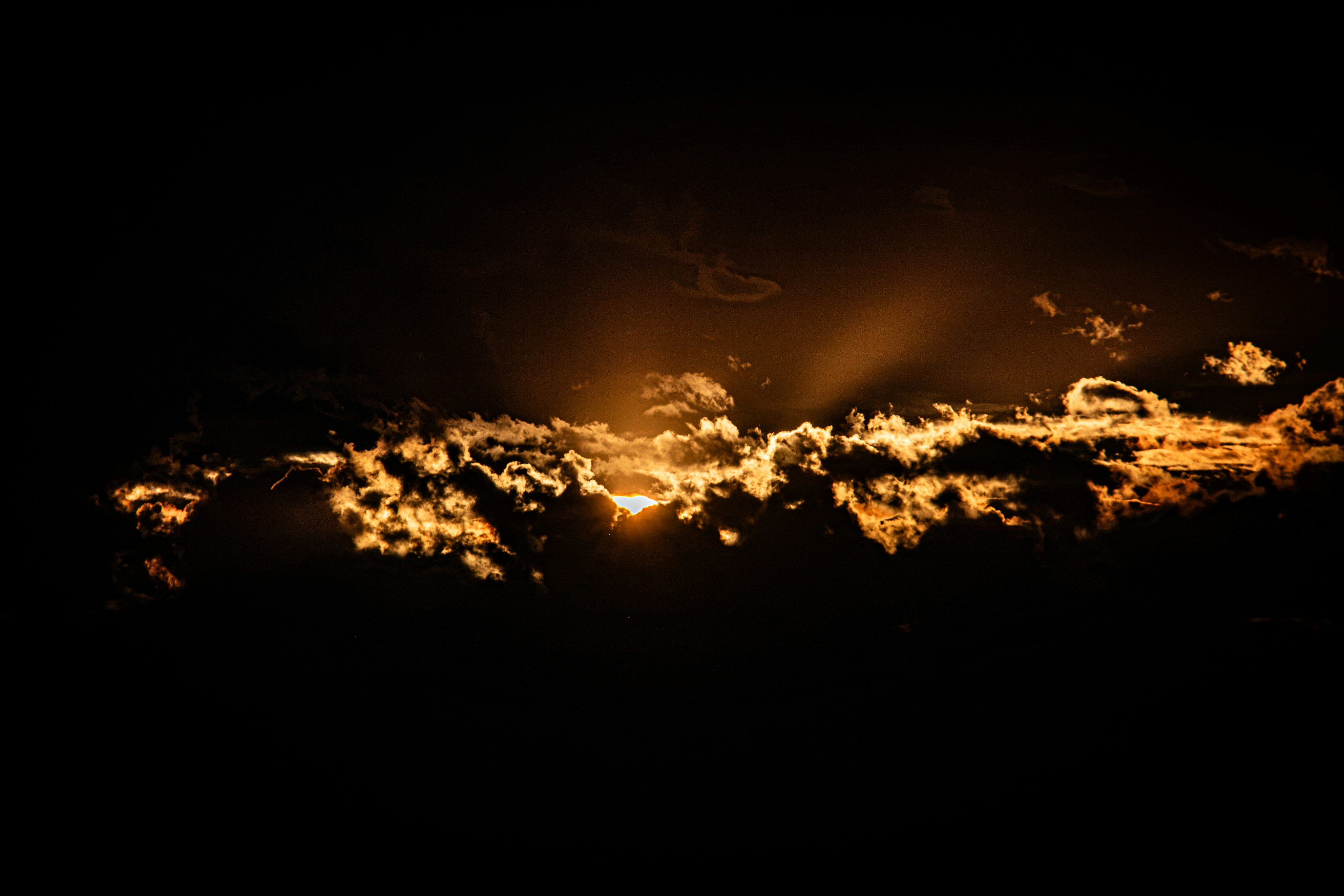 Fiery horizon: sun’s glow seeping through a cloud break at dusk
