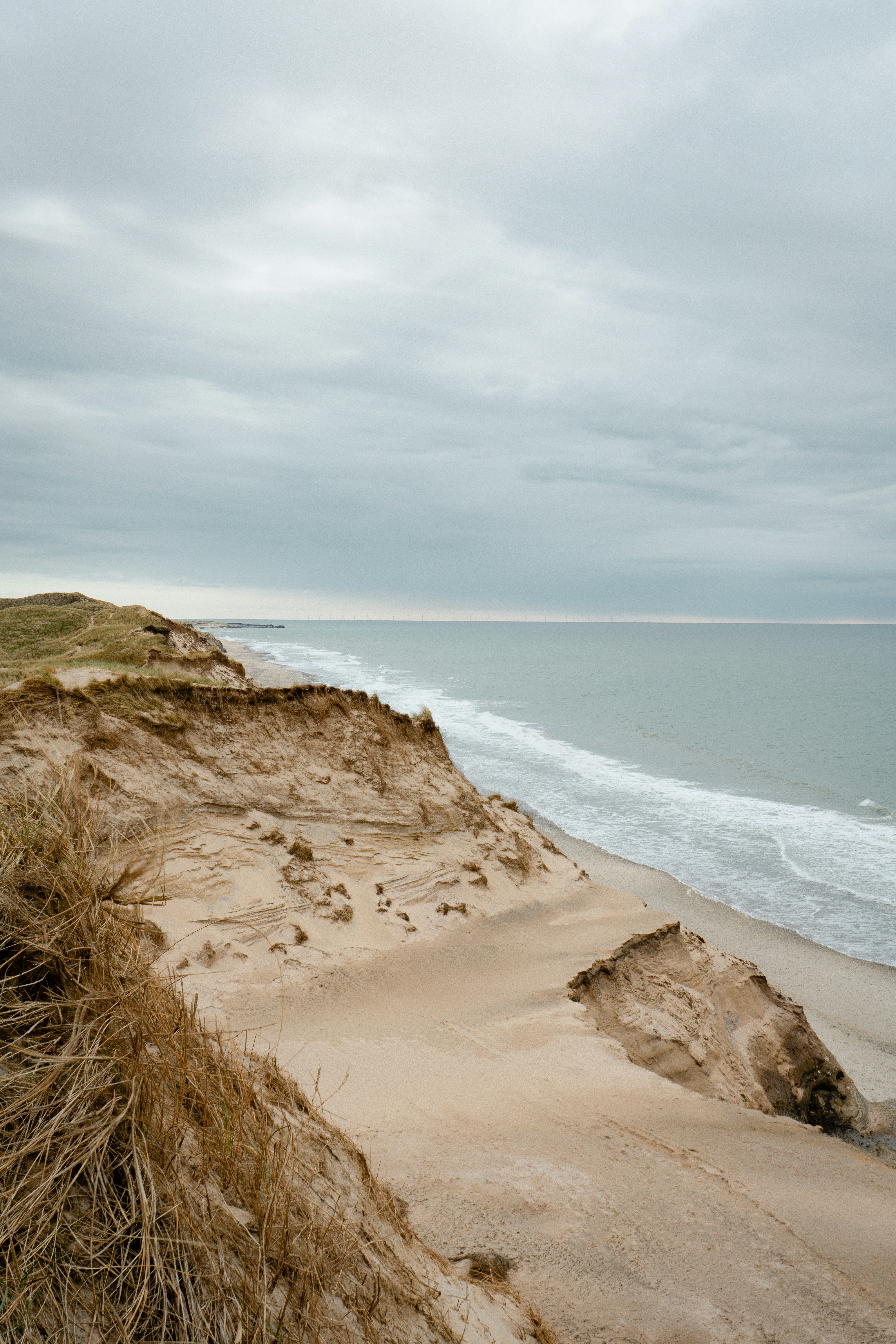 Cliffside Dunes by a Quiet Sea under Overcast Sky