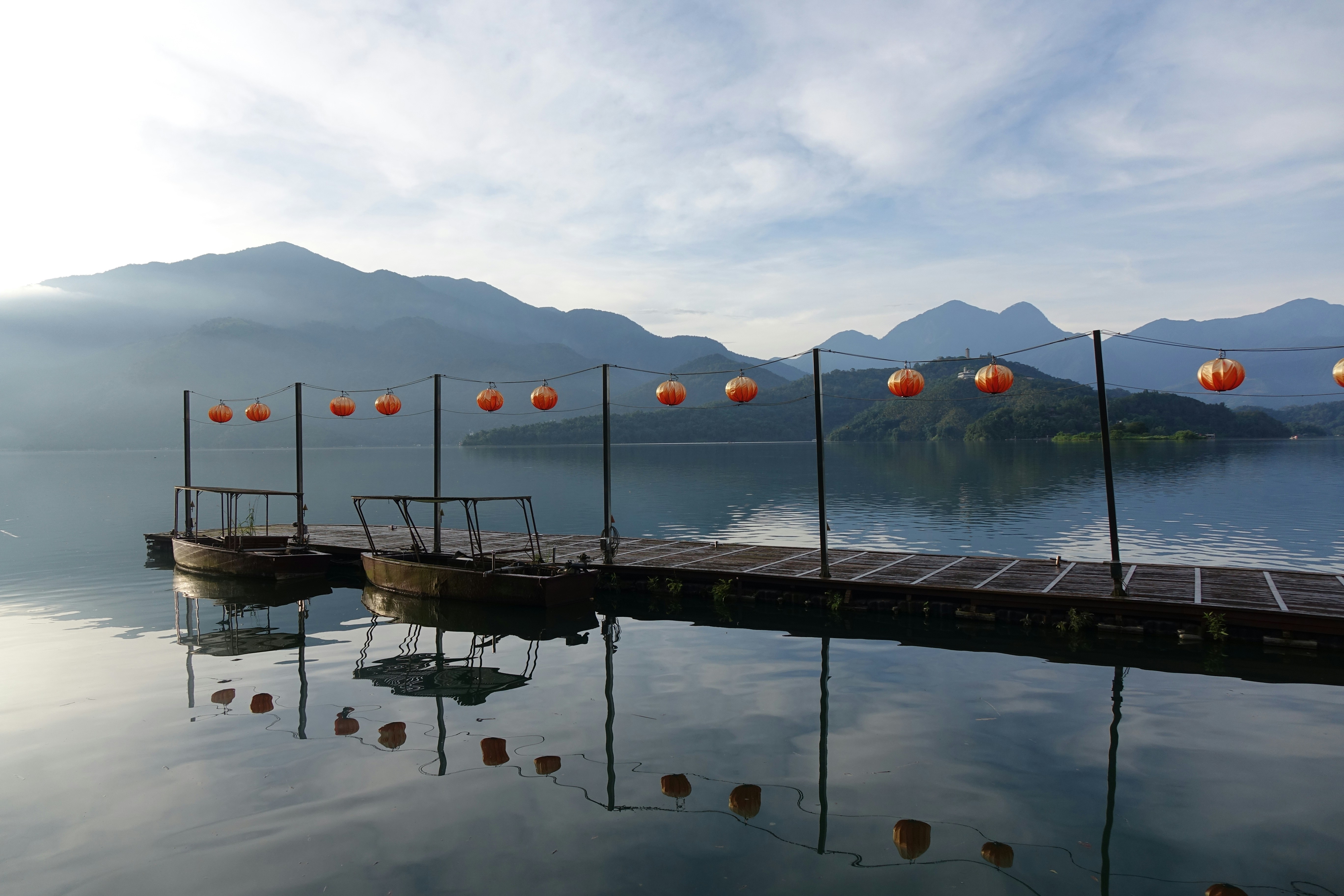Lanterns on the Glass: Boats, Pier, and Mountain Reflections