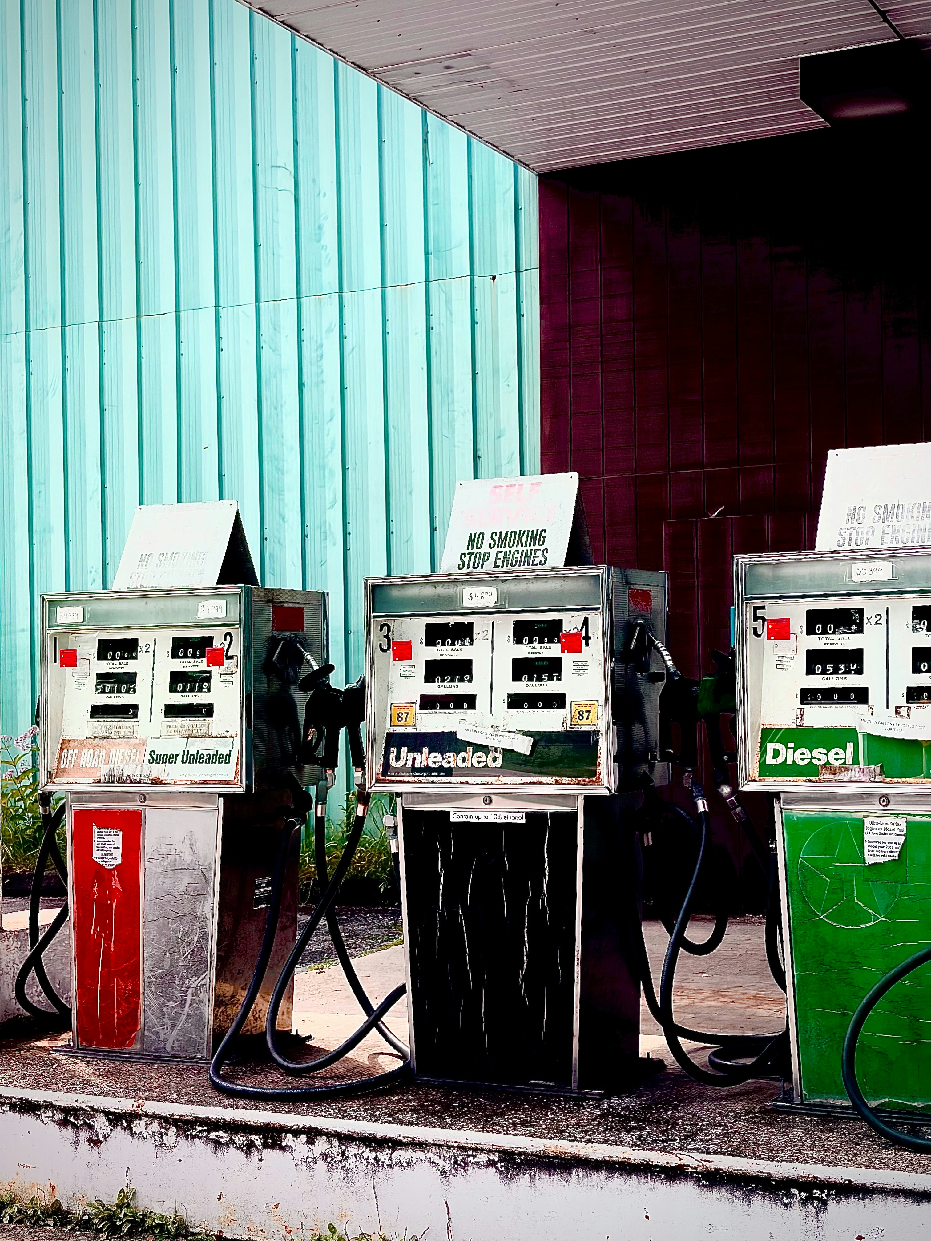 Ephemeral Petrol Parlor: A Row of Weathered Pumps Under Teal and Burgundy Canopy