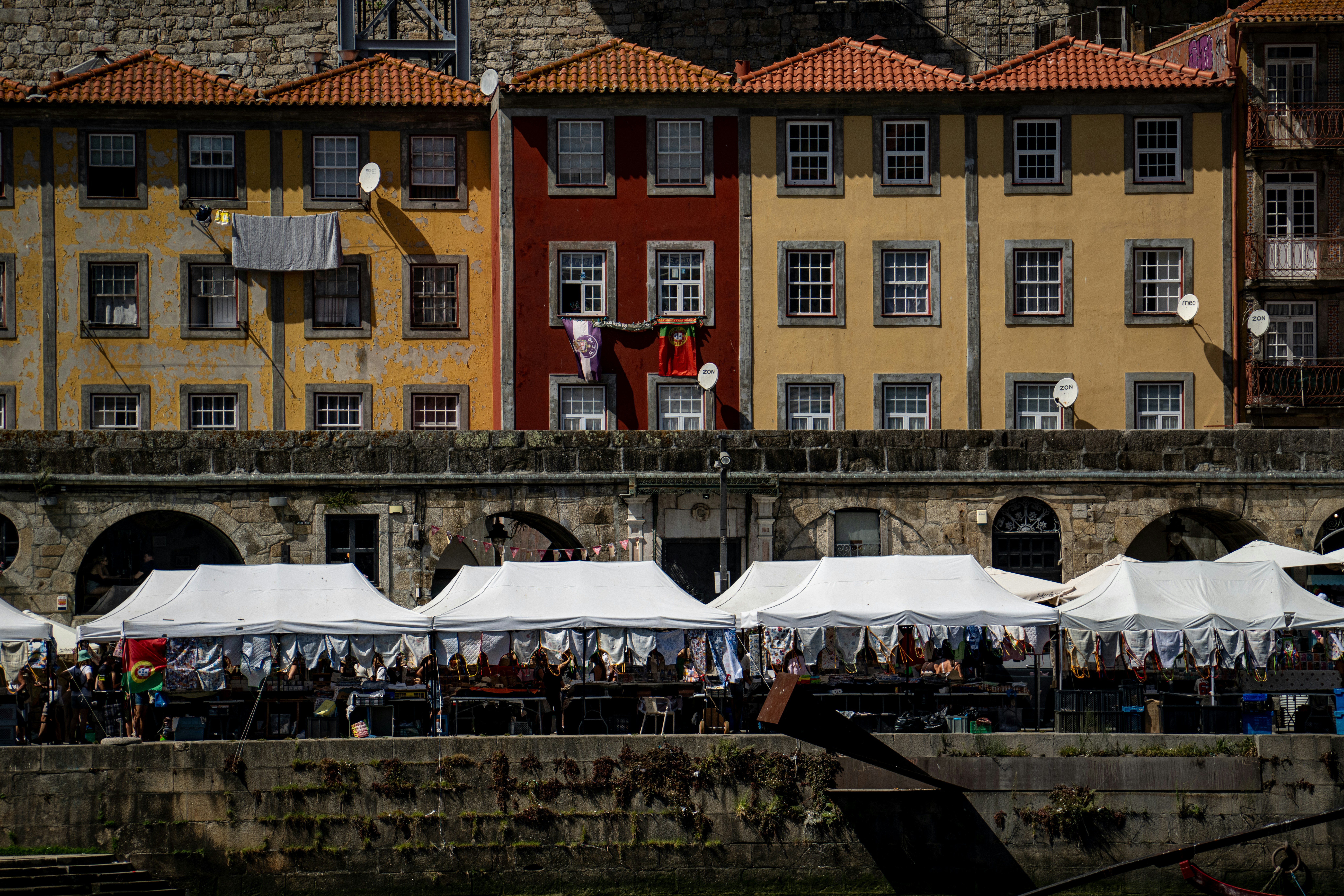 Colorful riverside market canopies under a historic building row