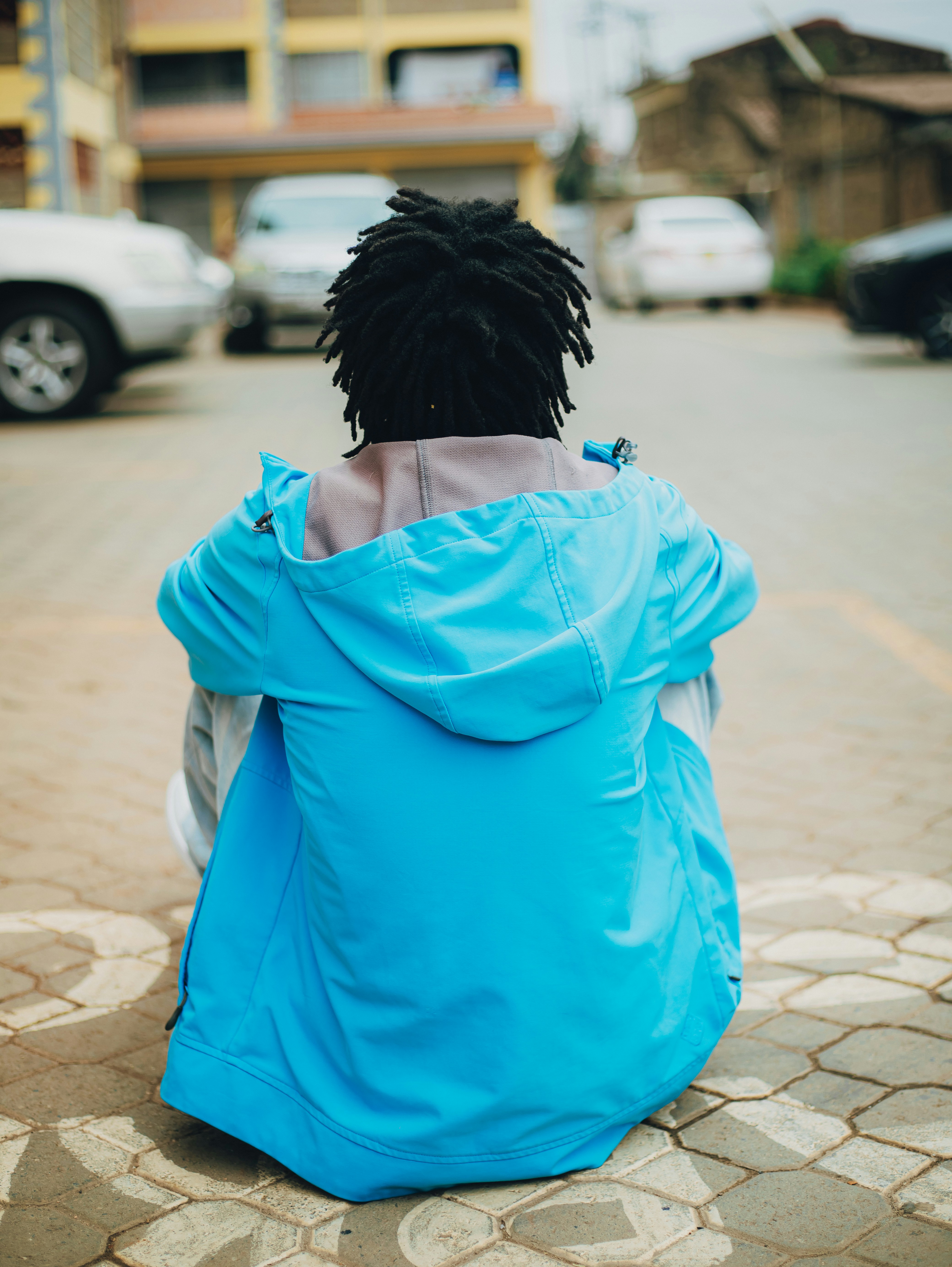 Back to the City: A Child in a Bright Blue Jacket Sits in a Quiet Street