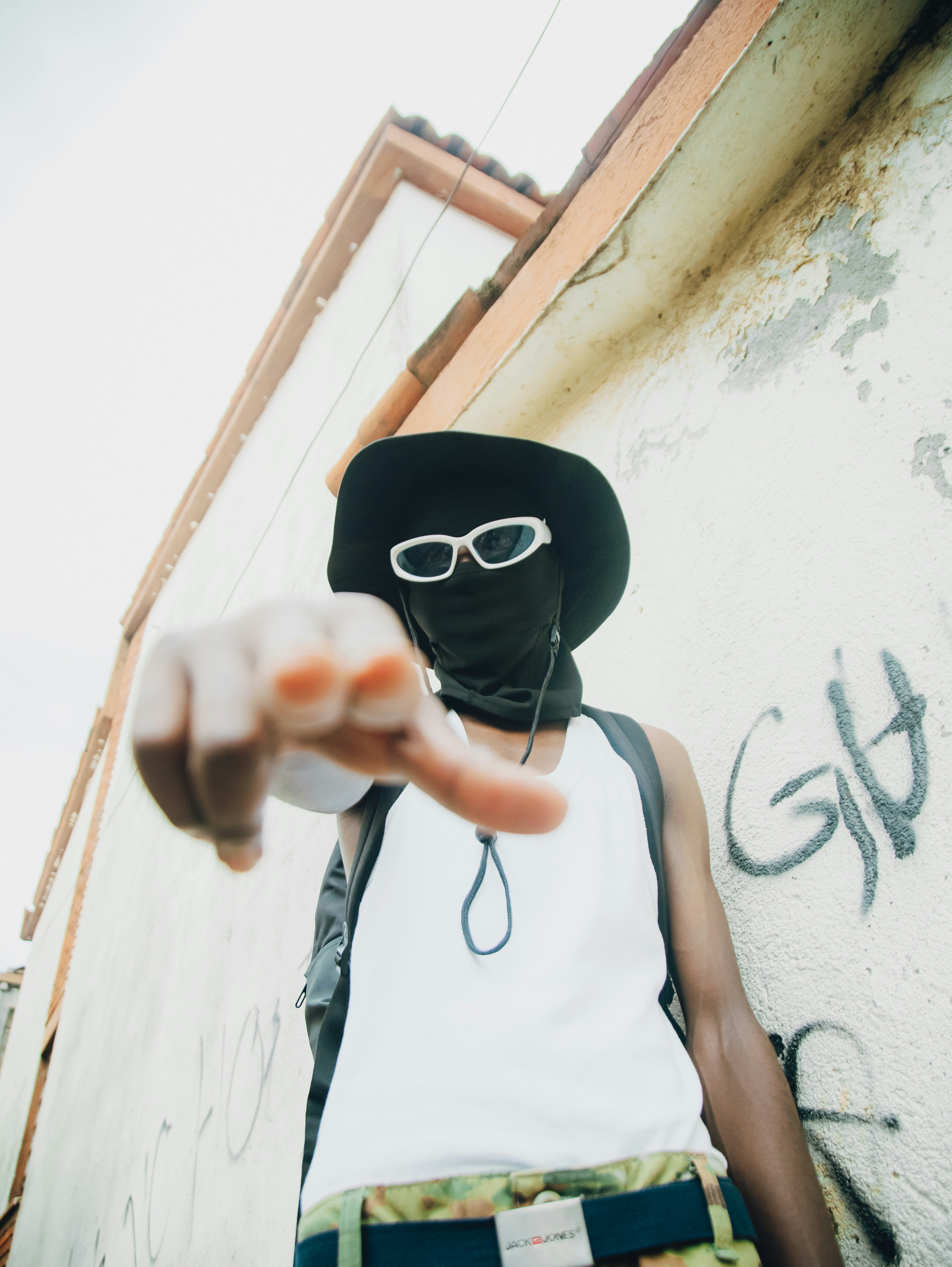Masked Maverick Reaching Forward in a Graffitied Alley