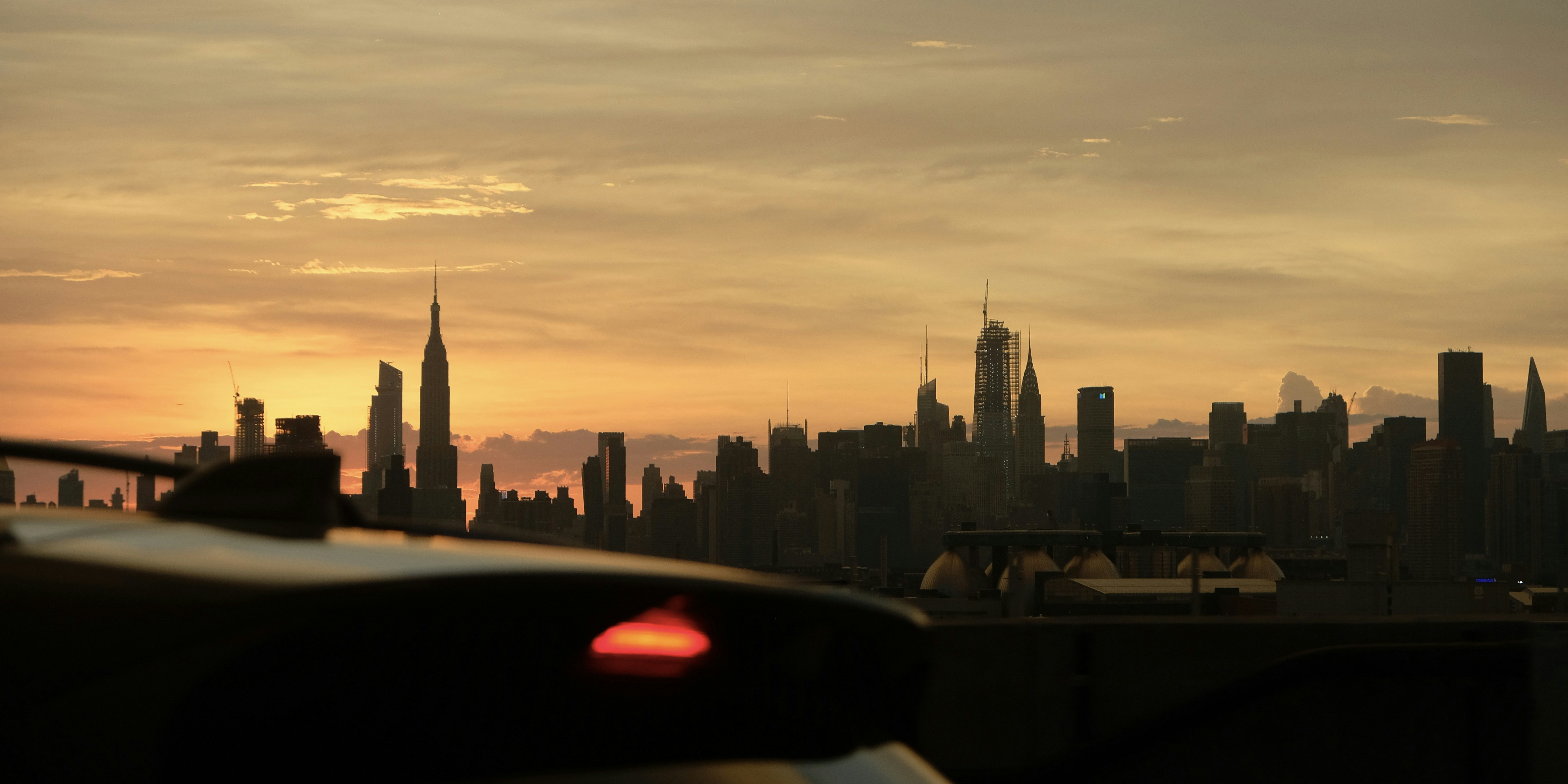 The New York City skyline in silhouette against a warm orange sky